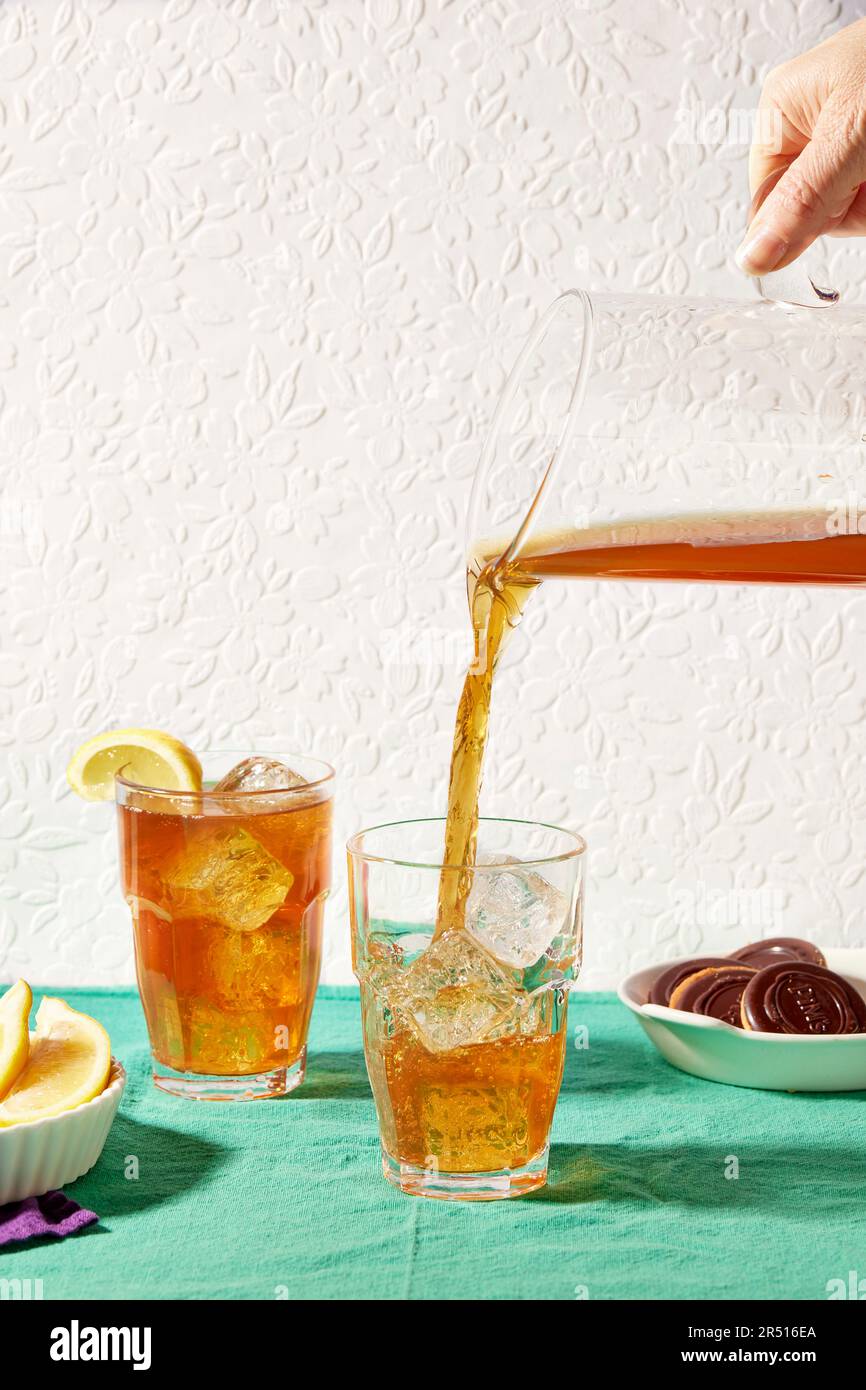 Pouring iced tea into a glass filled with ice cubes Stock Photo - Alamy