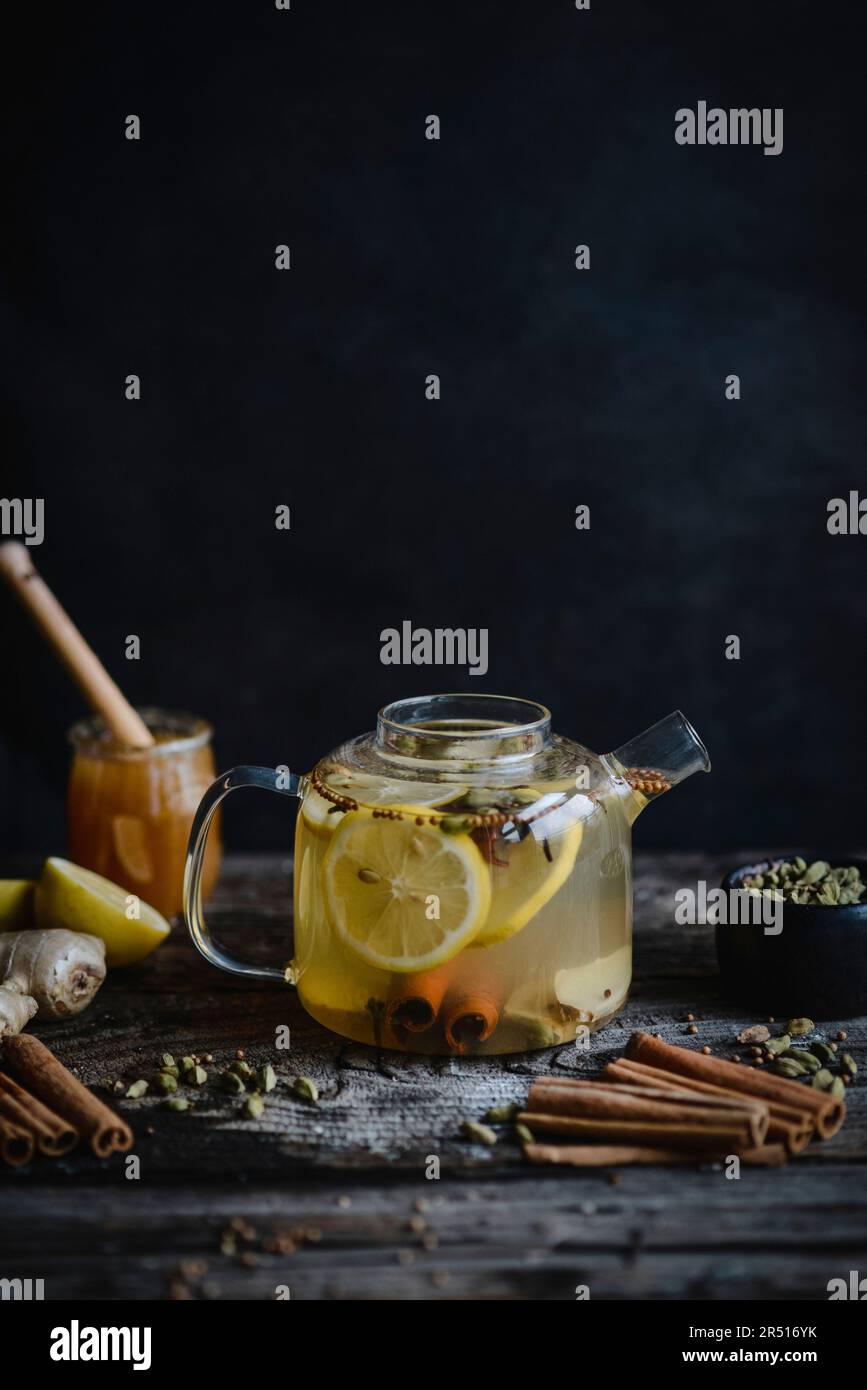 Spicy winter tea with lemon, cinnamon and cardamom in glass teapot ...