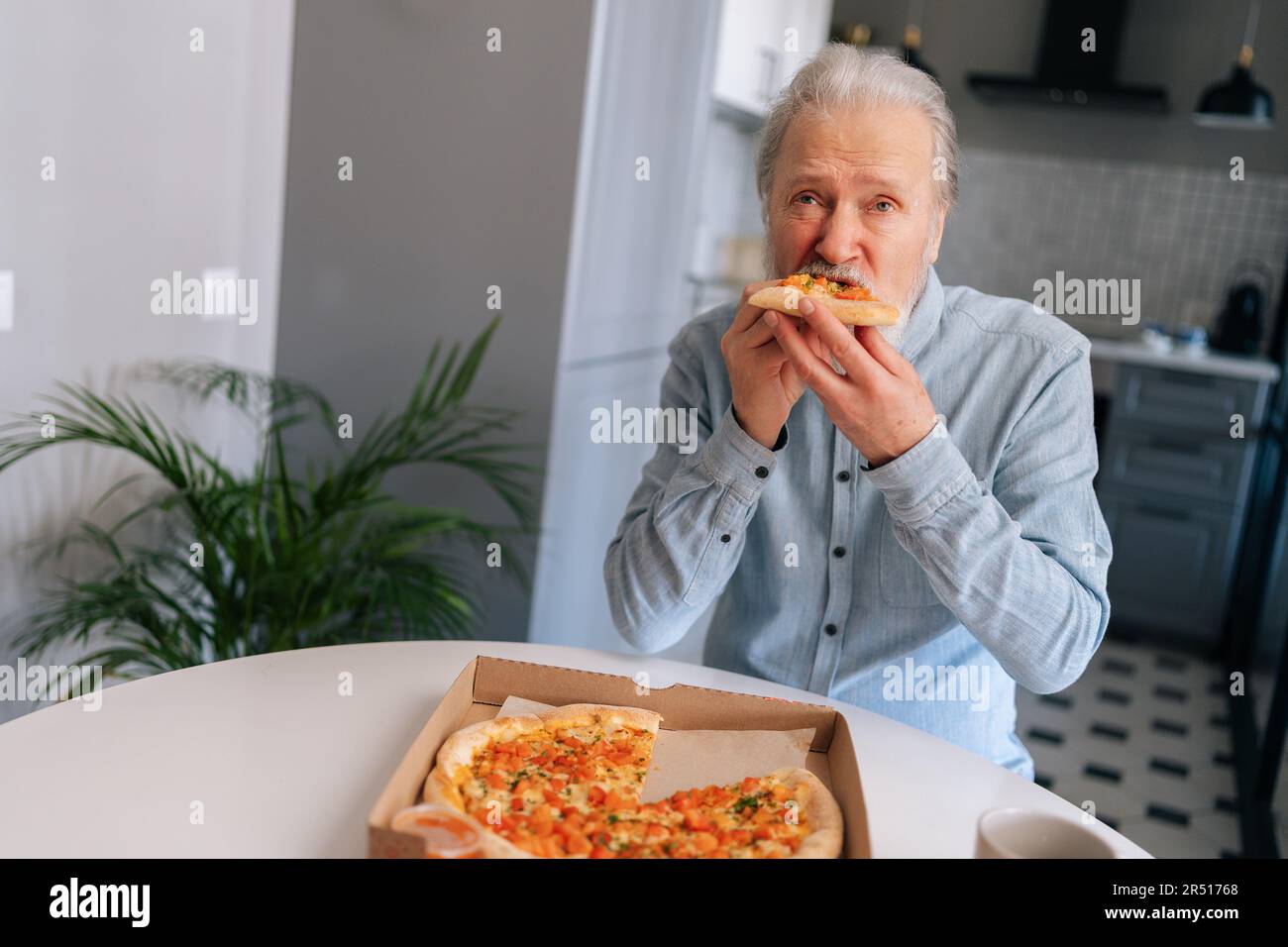 Vertical portrait of hungry gray-haired mature male enjoying to eat ...