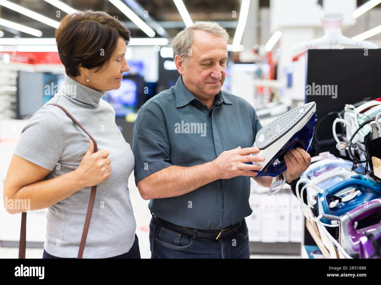 Older couple picking out new clothes iron to buy in electronics ...