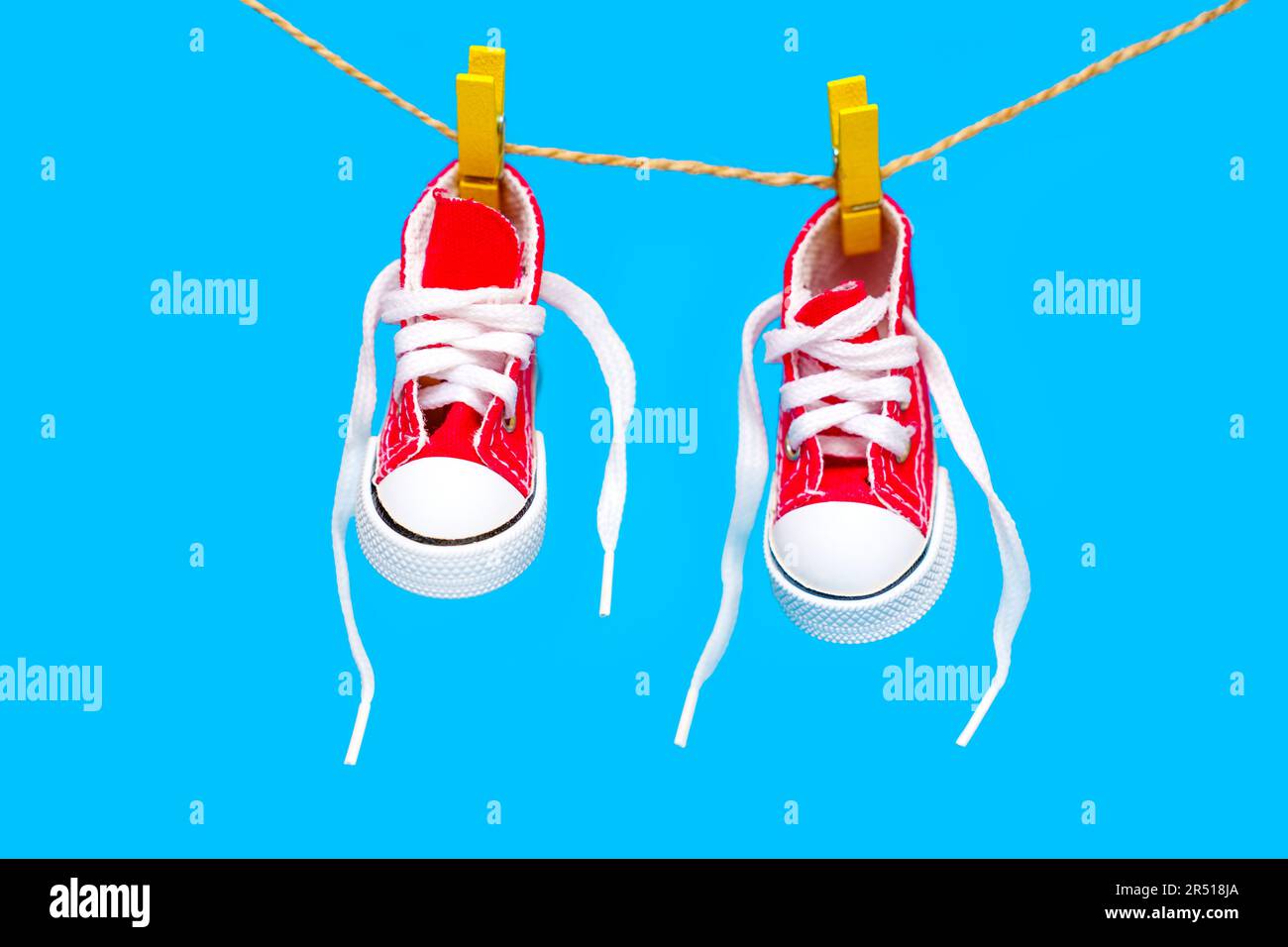 Miniature red canvas shoes with white laces and rubber soles are ...