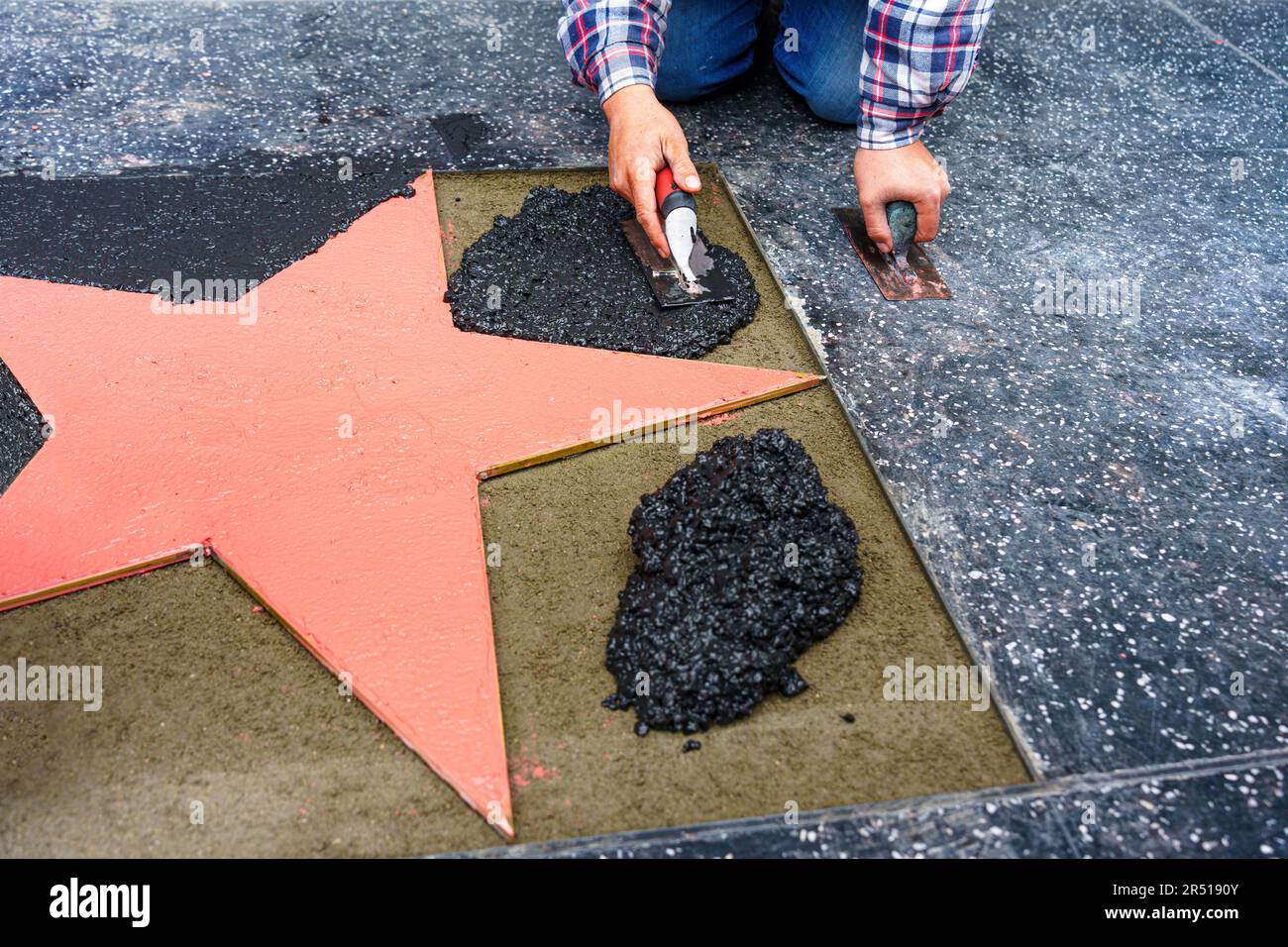 Worker placing terrazzo pavement around a star on the Walk of Fame in ...