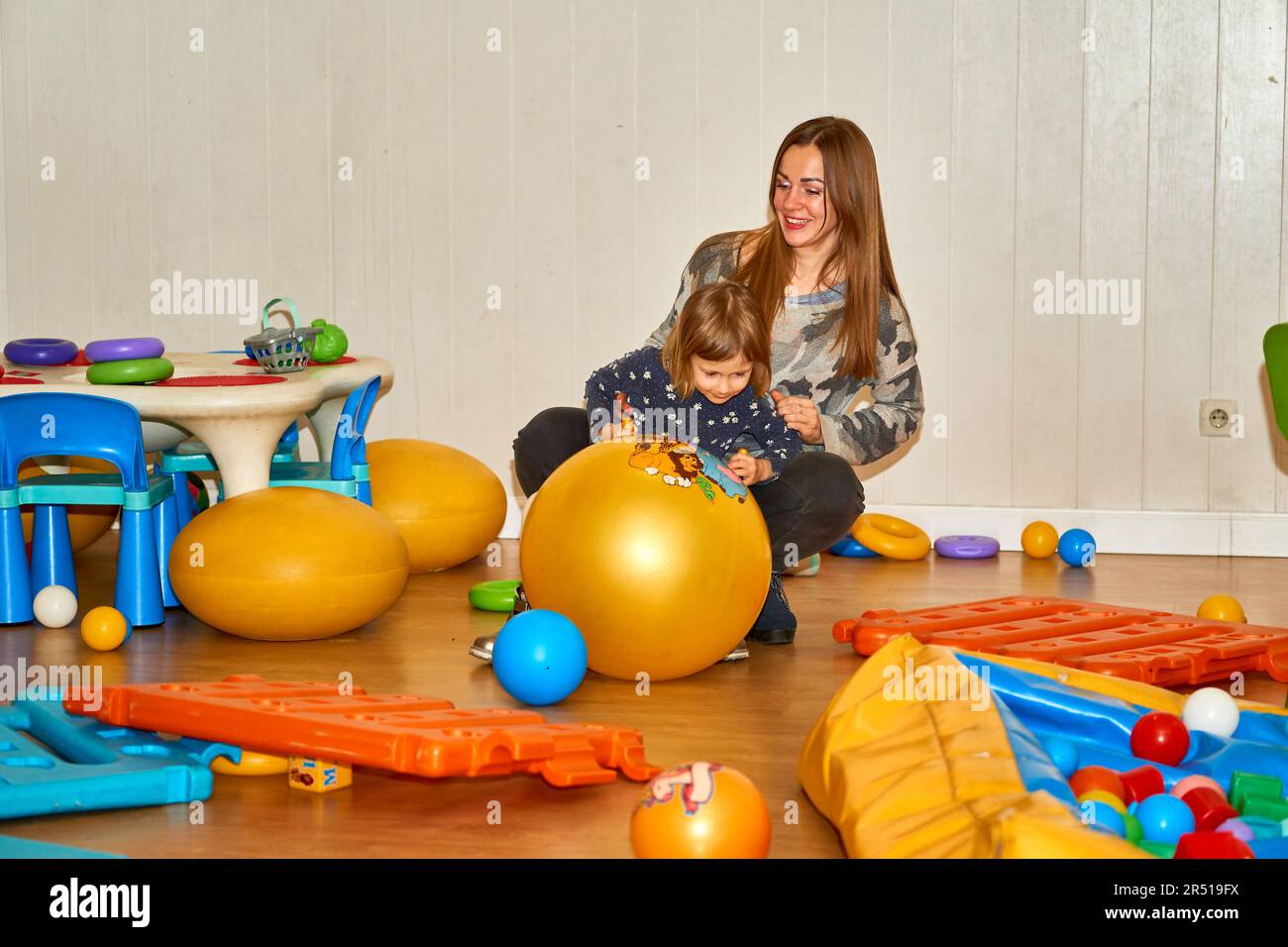 Pretty mother playing with cute daughter baby girl in playroom in ...