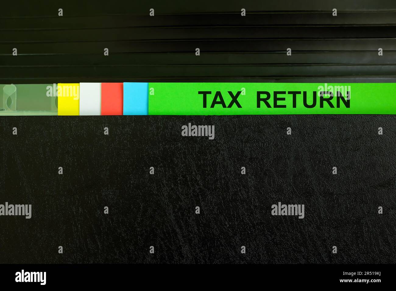 Hand picking tax return file record in black binder folder. Filing ...