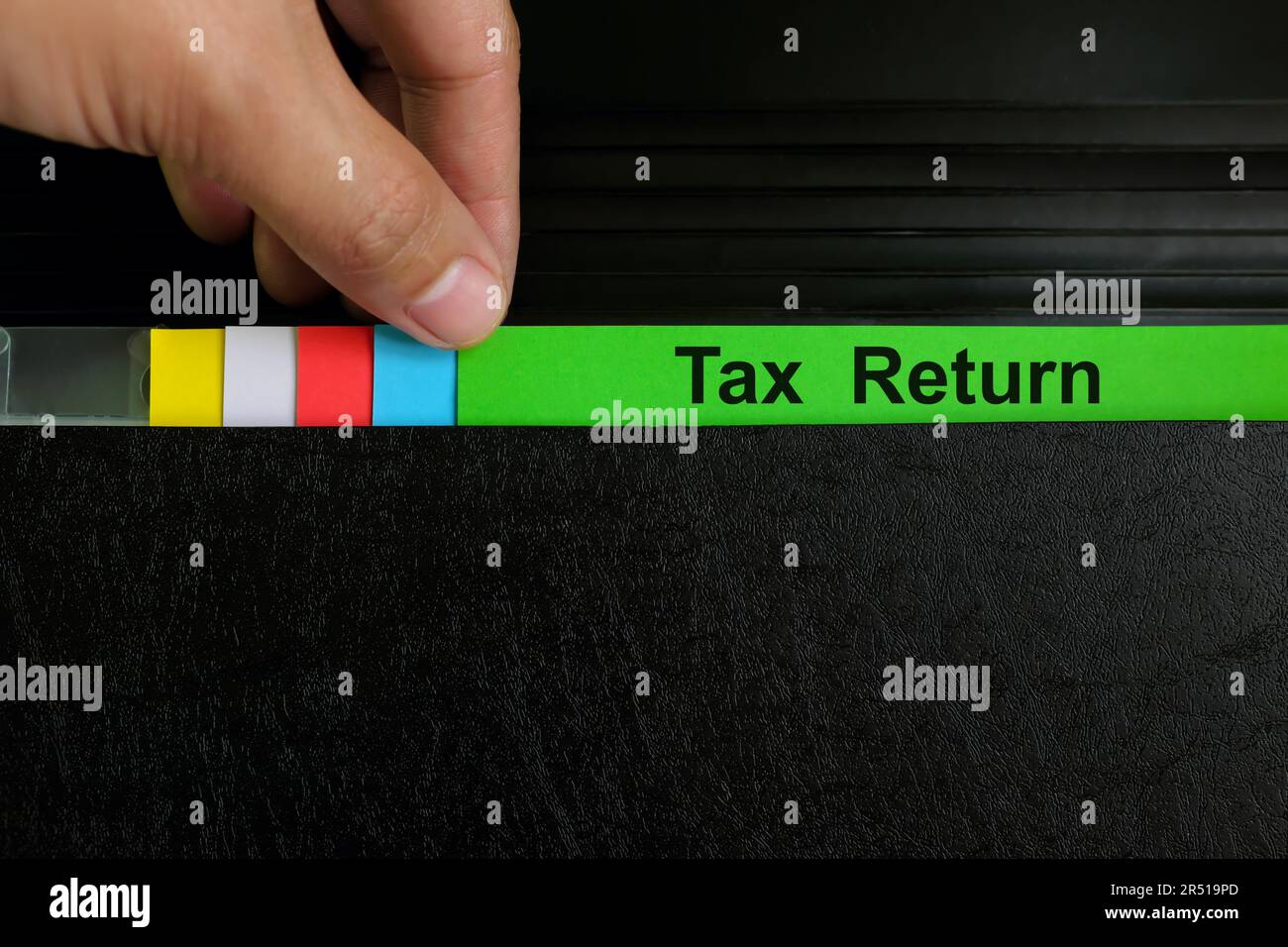 Hand picking tax return file record in black binder folder. Filing ...