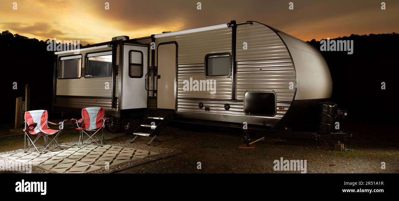 Brightly lit camping trailer at sunset with a dark ridge and bright ...