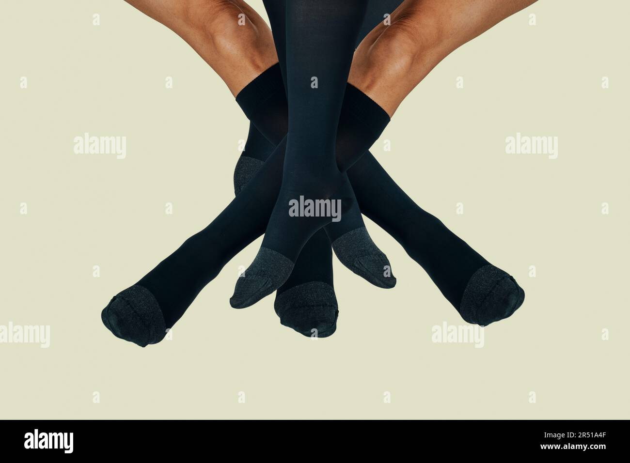 some legs wearing black compression socks on an off-white background ...