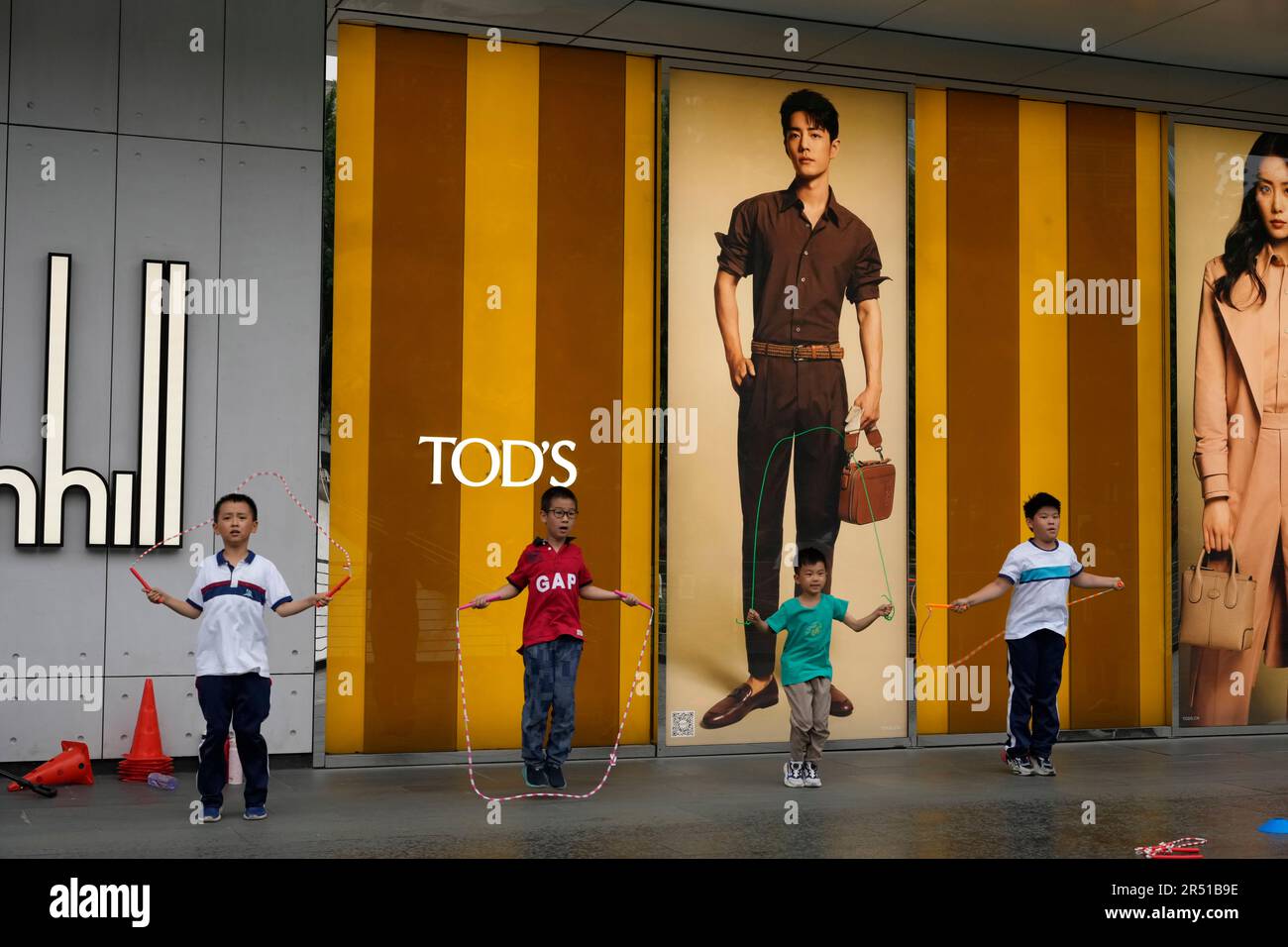 Children skip ropes near advertisements at a mall in Beijing, Wednesday ...