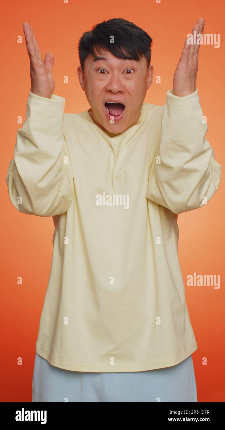 Excited amazed asian man touching head and showing explosion, looking ...