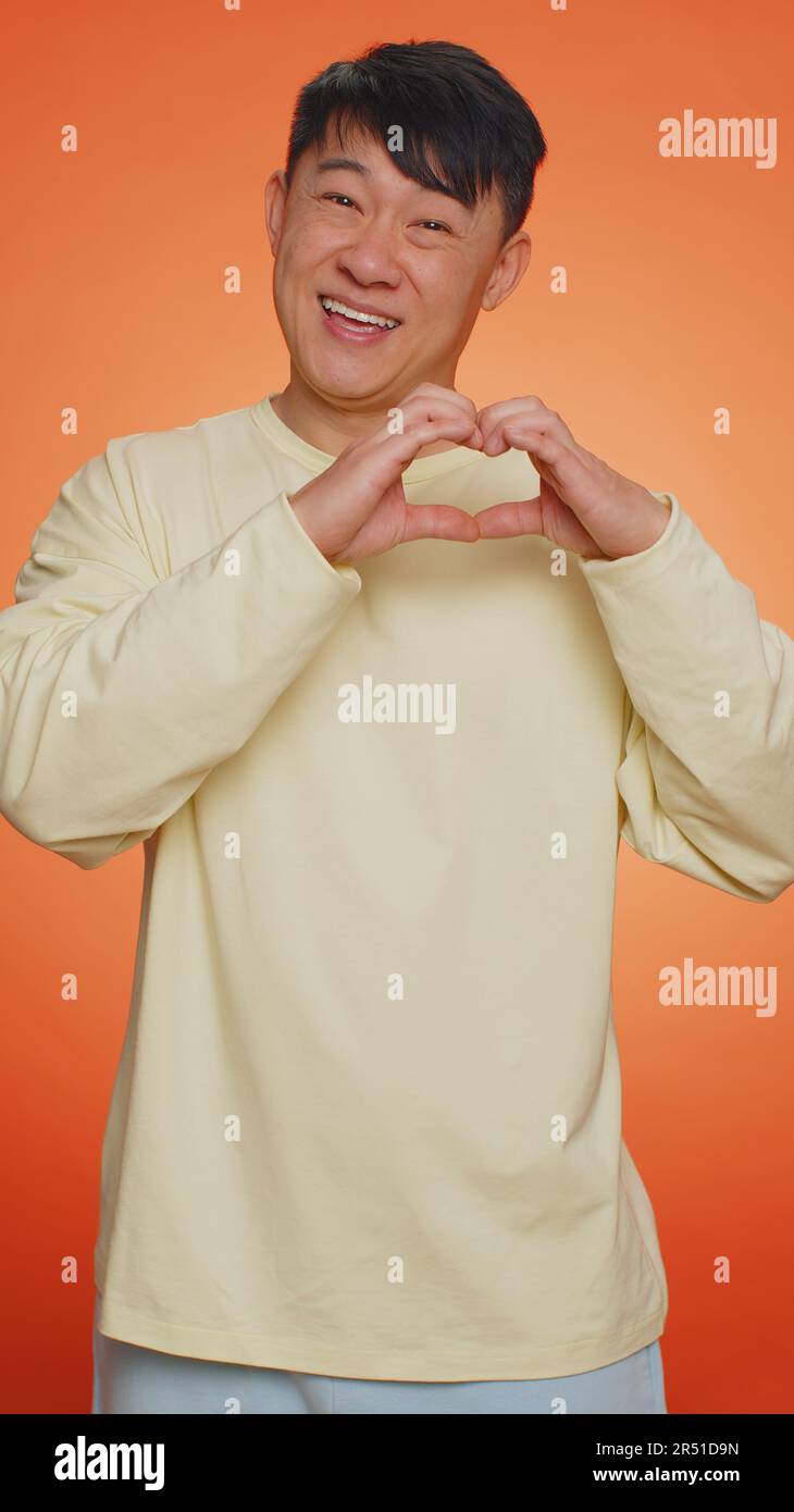 Man in love. Smiling asian man makes heart gesture demonstrates love ...