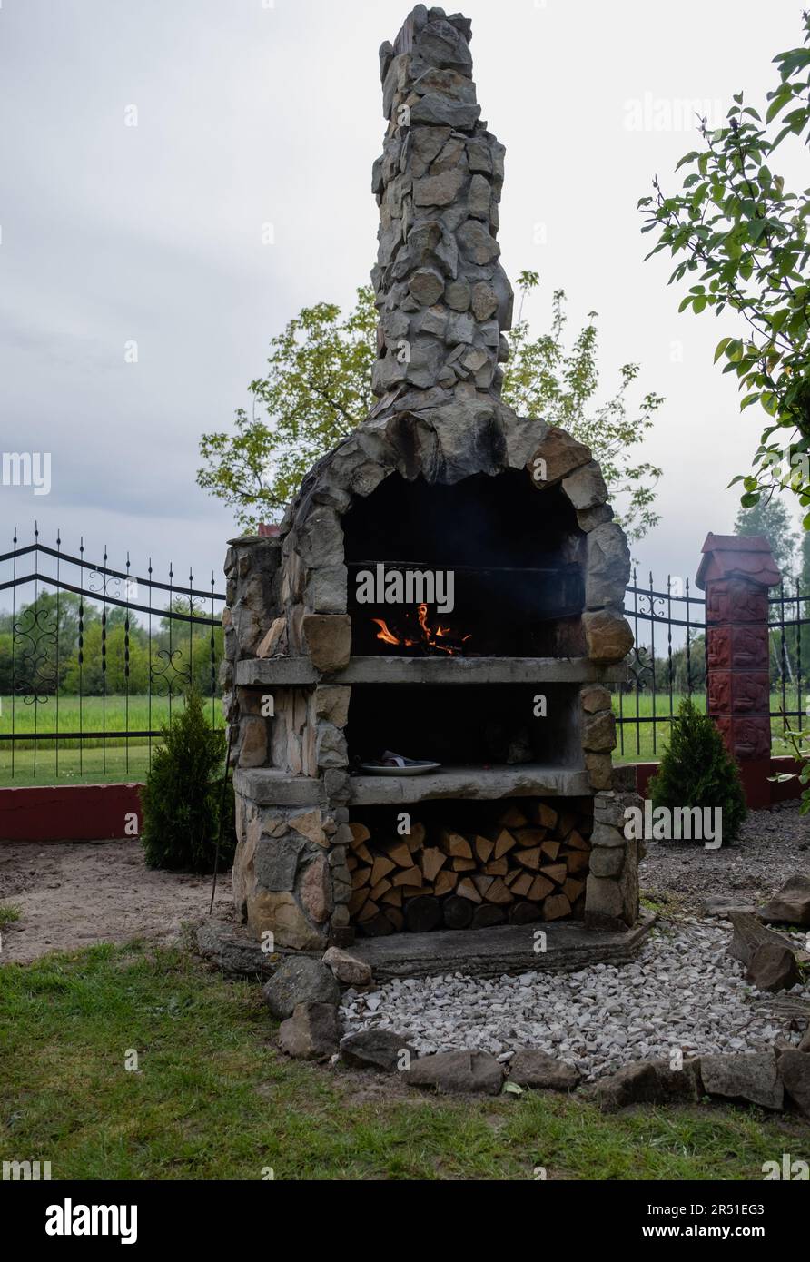 Stone barbecue in the garden with fire - fence and plants in the ...