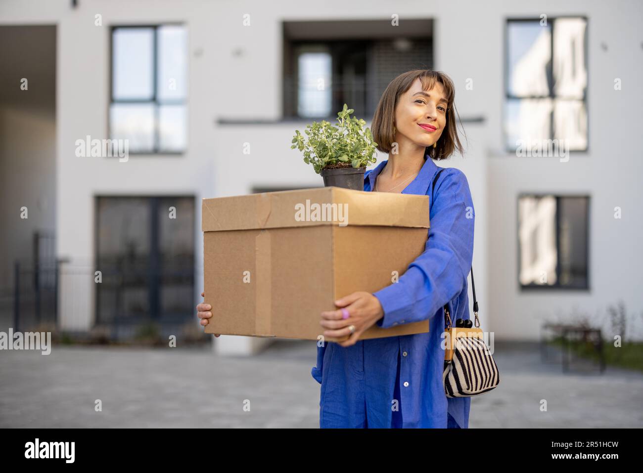 Woman carrying cardboard box at inner yard of apartment building Stock ...