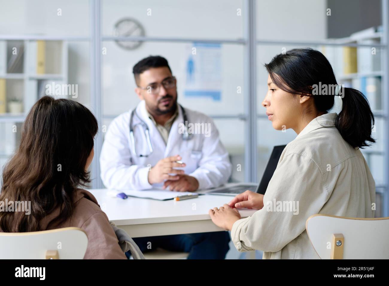 Young woman with child discussing treatment with doctor during their ...