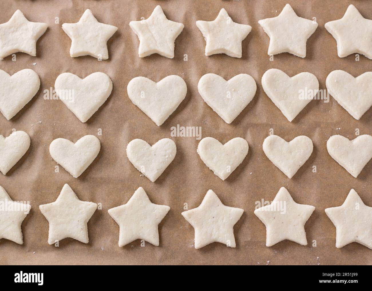Raw cookies in the form of stars and hearts on a baking sheet with ...