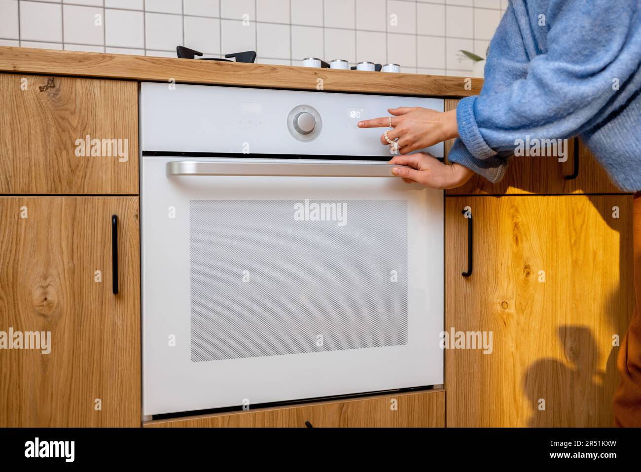 Woman using modern oven on kitchen Stock Photo - Alamy