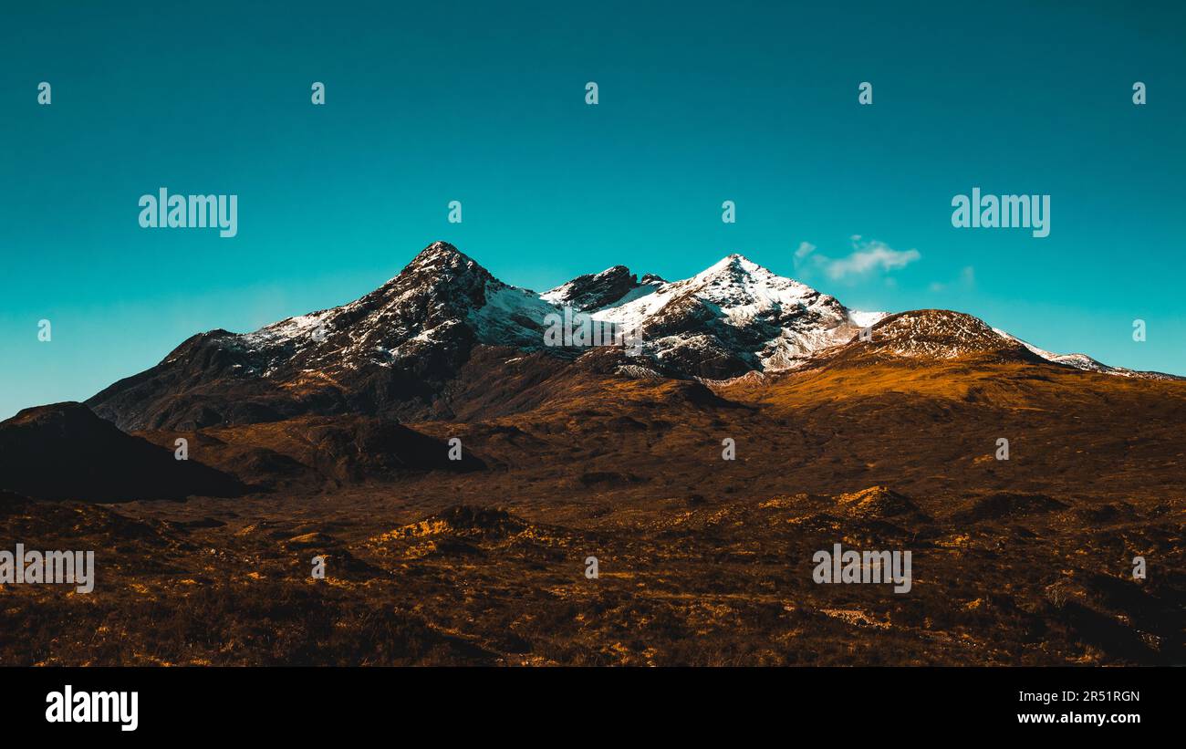 A dramatic rugged landscape with sharp peaks of mountains covered with ...