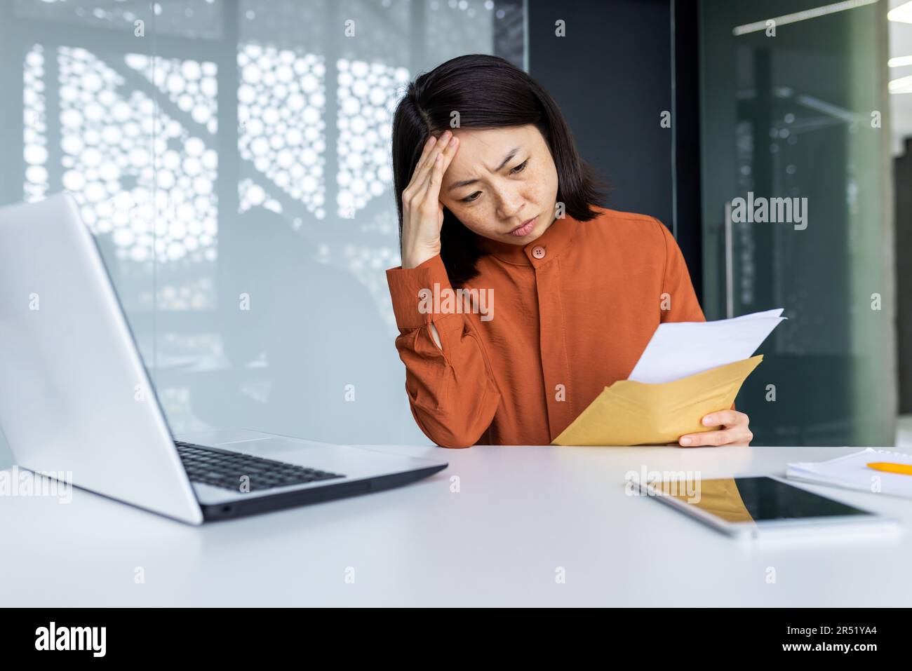 A young Asian woman, secretary manager, accountant is worriedly holding ...