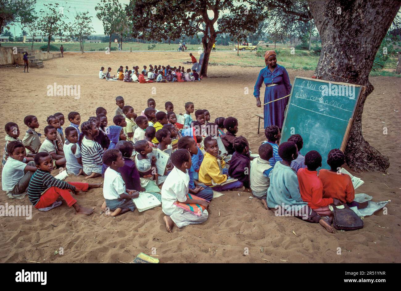 Mozambique, Xai-Xai; Group of children is sitting under a tree, getting ...