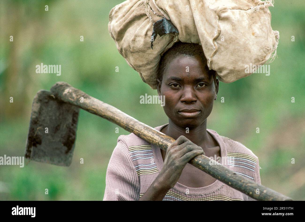 Mozambique, Gaza province; Portrait of a woman carrying a hoe over the ...