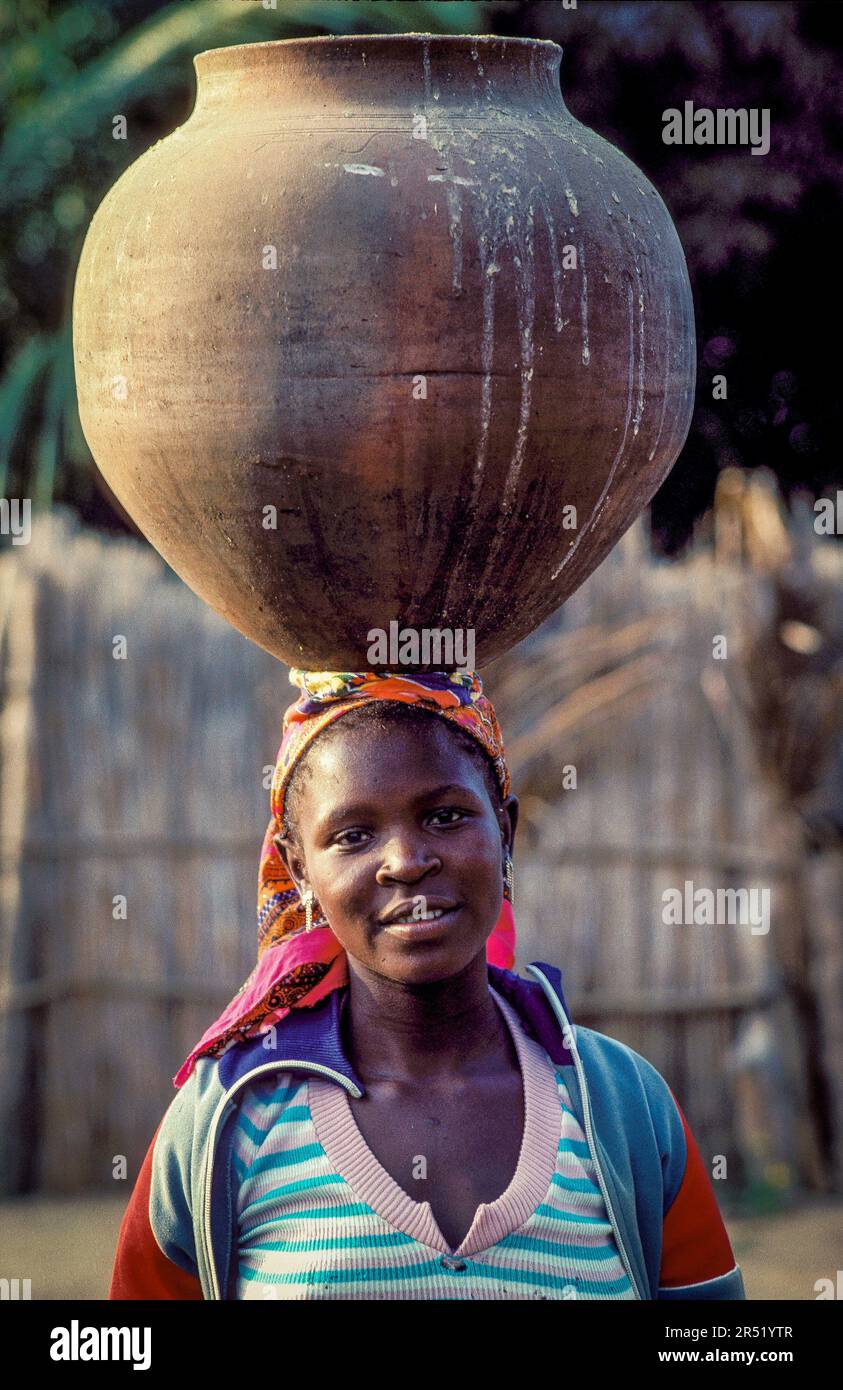 Mozambique, Xai-Xai region; Woman carries a clay jar filled with water ...