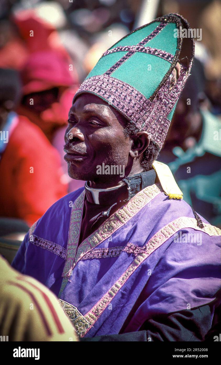 Mozambique, Maputo; A black bishop wearing a purple robe and a green ...