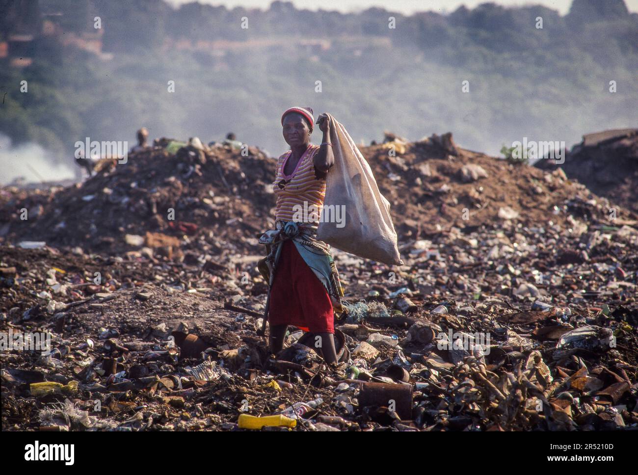 Mozambique, Maputo; Woman is standing on a garbage dump, surrounded by ...