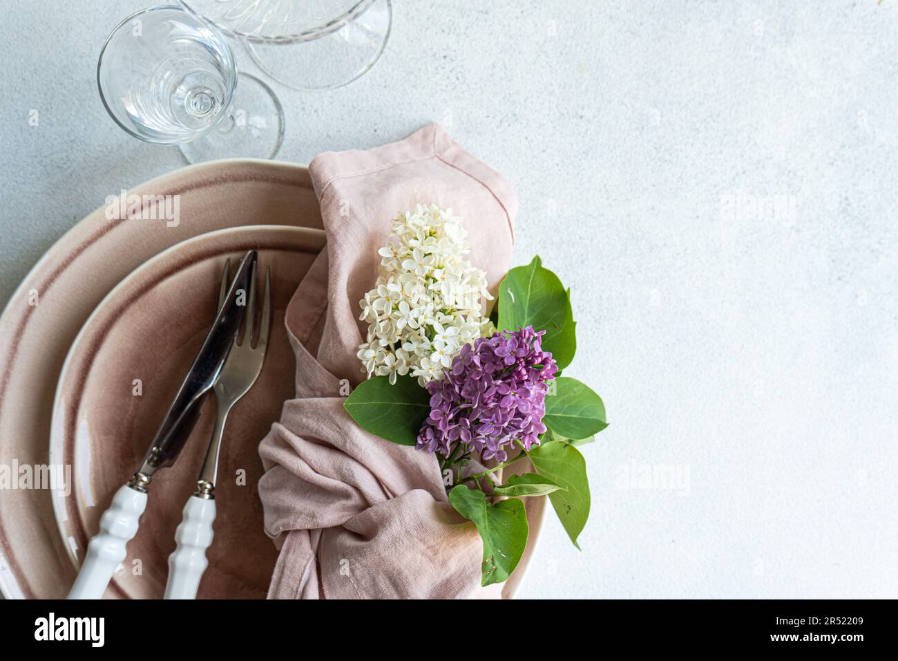 Top view of cropped table setting with lilac flowers on tableware in ...