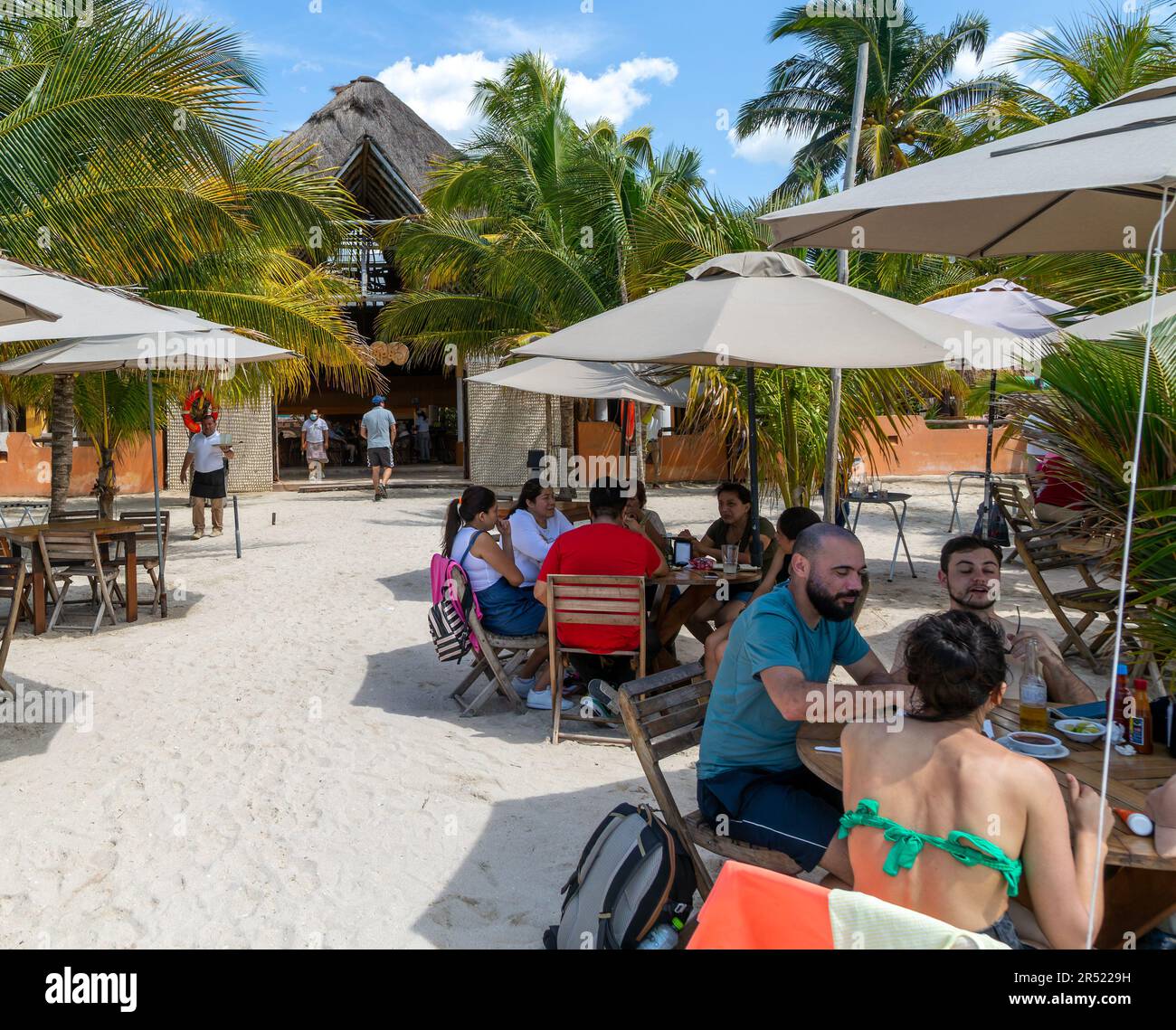 People eating at tables on beach, La Palapa restaurant, Celestun ...