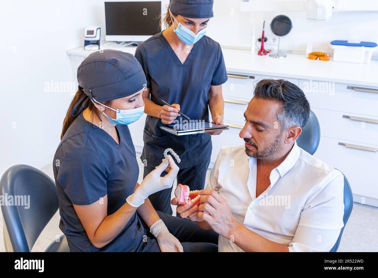 Female dentists in medical uniform with mask, latex gloves and tablet ...