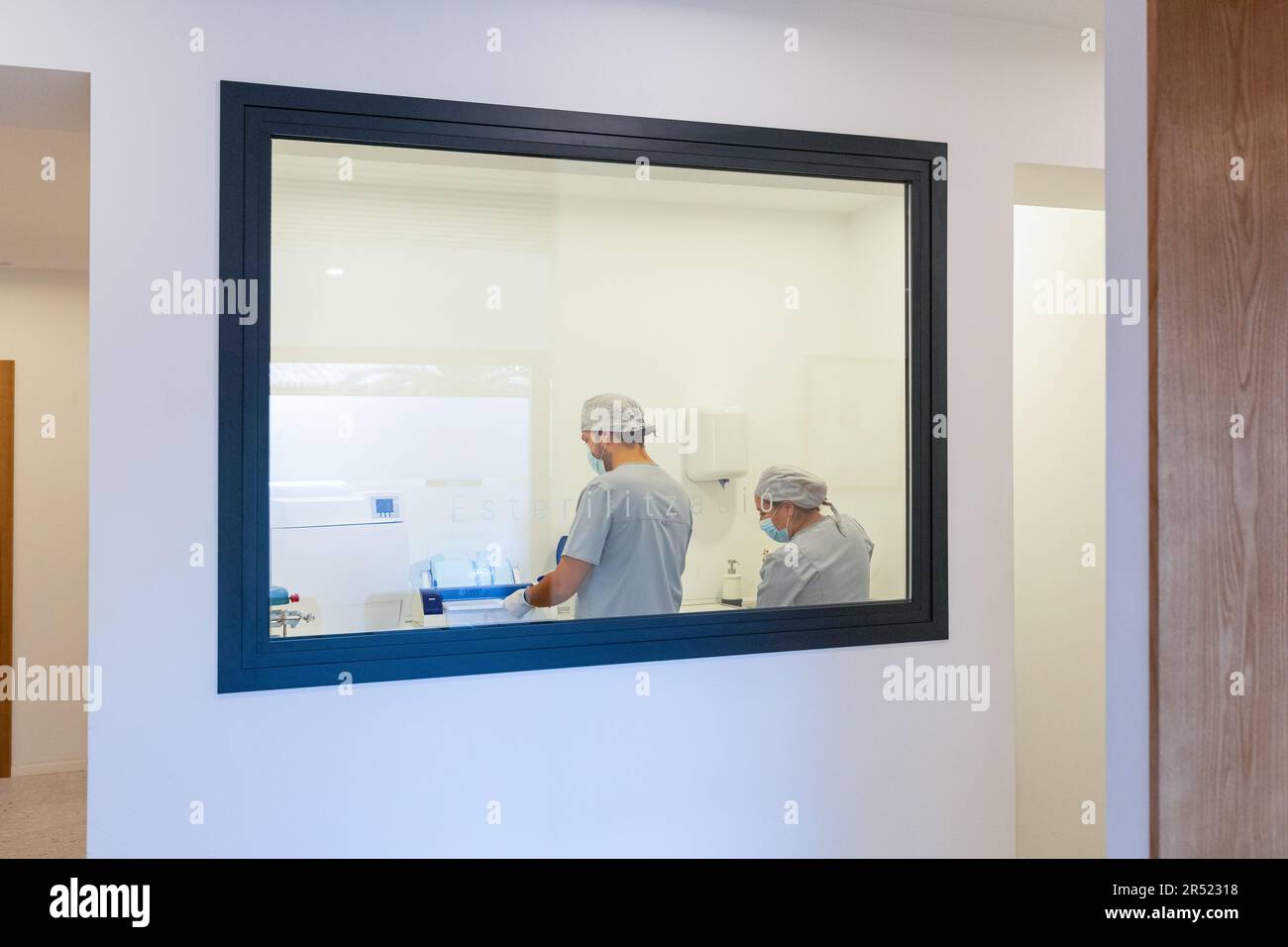 Through glass view of doctors in medical uniform standing near window ...
