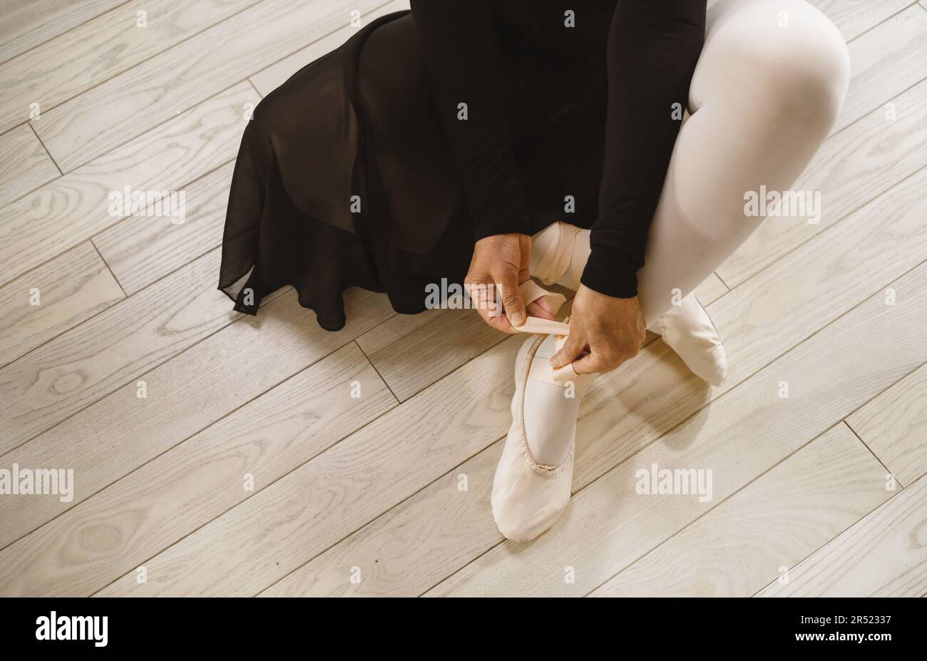 From above a faceless dancer in a black dress sitting on the floor and ...