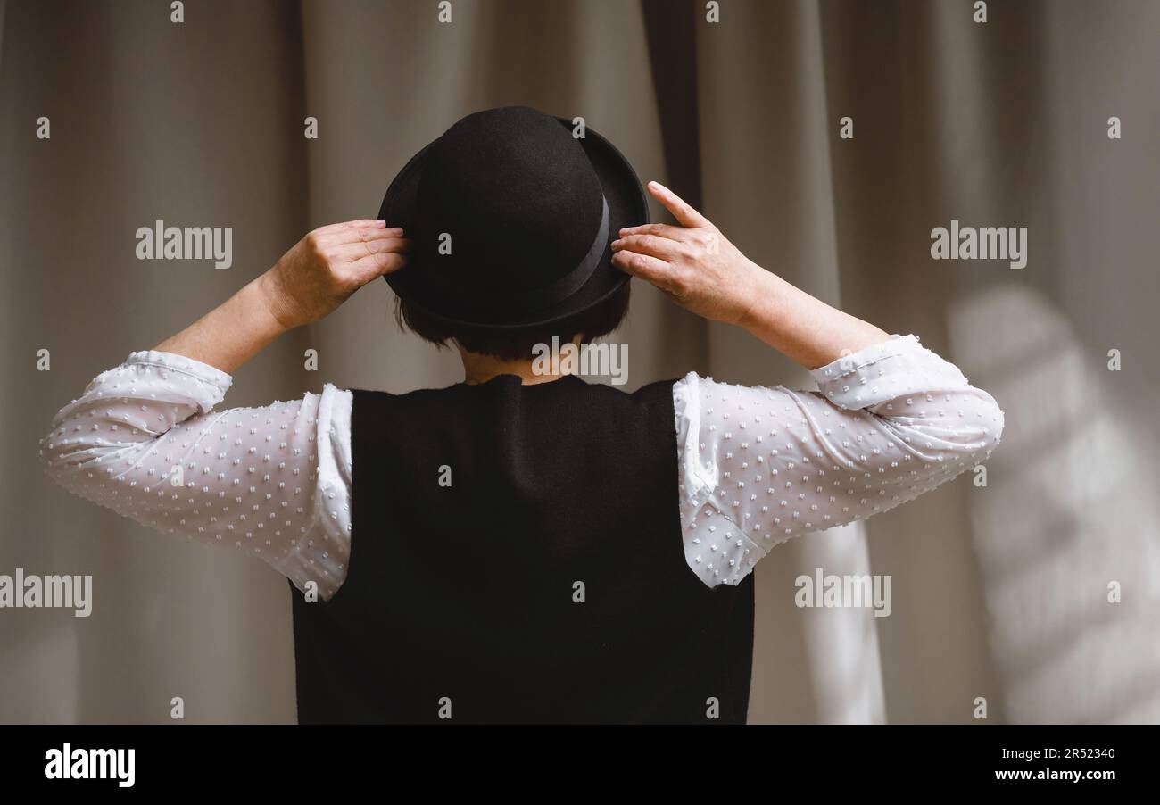 Back view of anonymous female model in elegant outfit putting on black ...