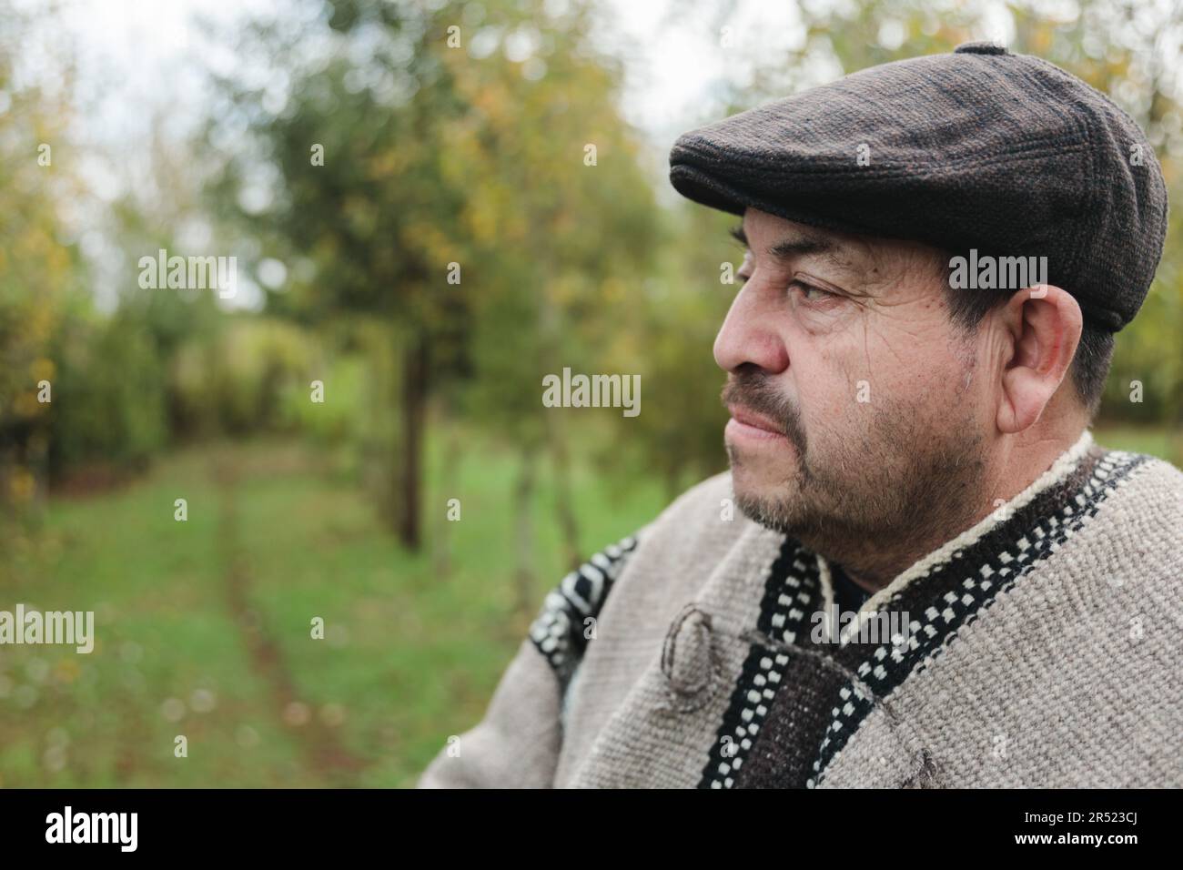 Thoughtful senior male in traditional Mapuche clothing and beret ...