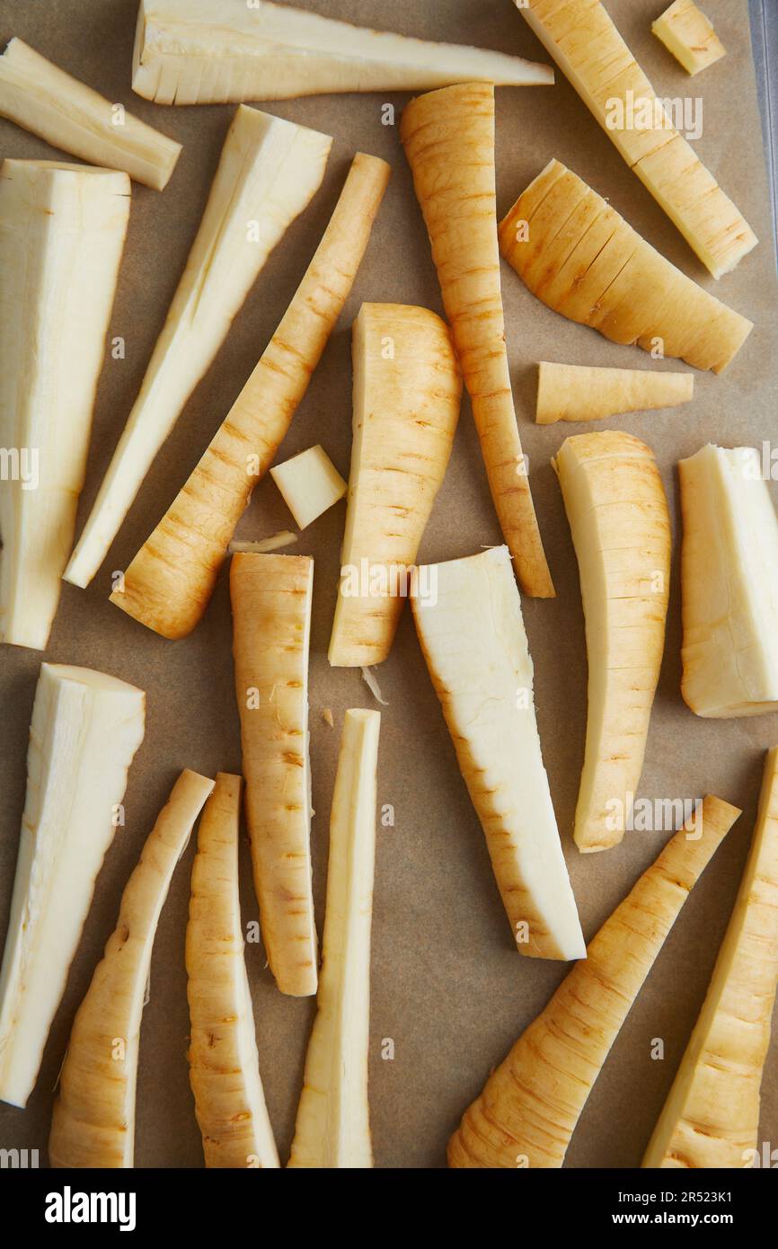 Top view of uncooked sticks of raw parsnip placed on parchment paper ...
