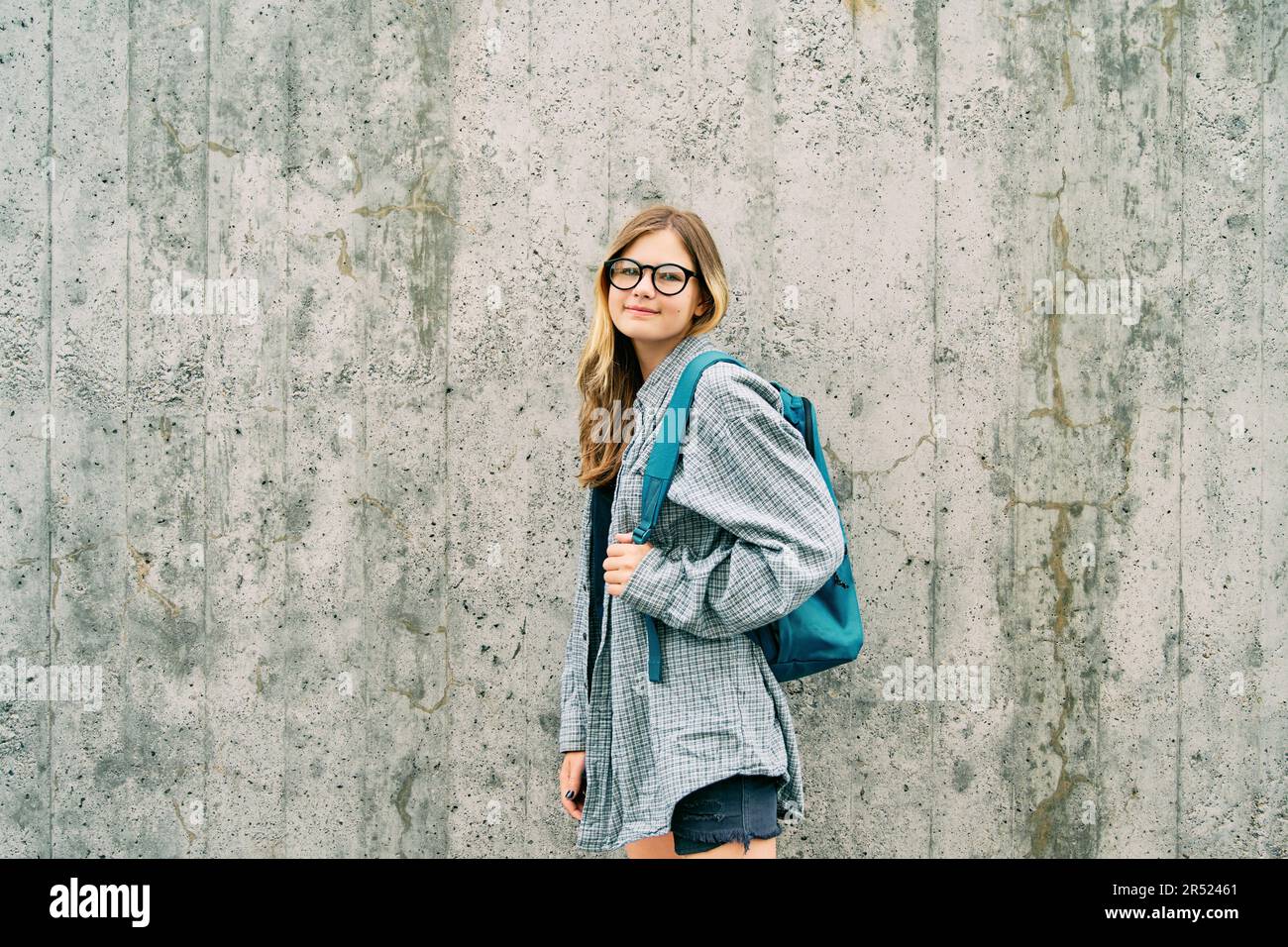 Outdoor portrait of young teenage kid girl wearing glasses and backpack ...