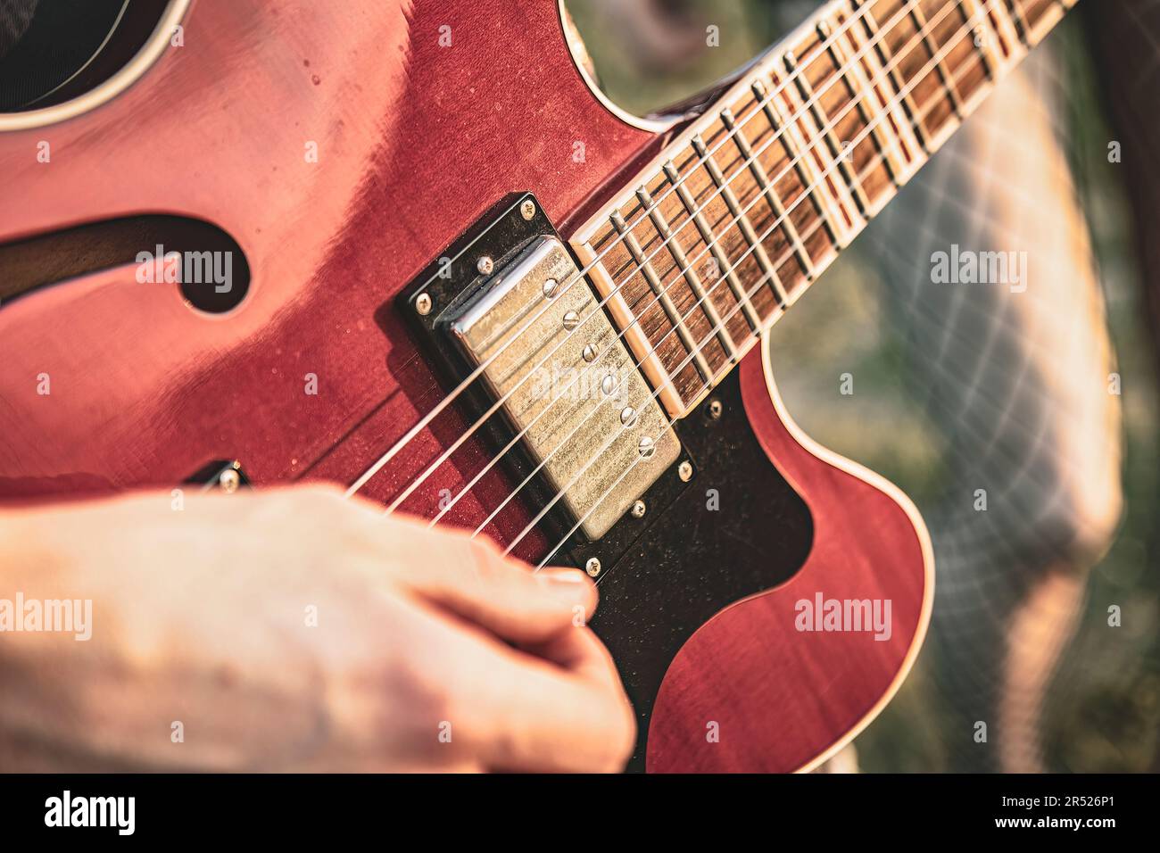 Close-up detail of a hand strumming a guitar outdoors Stock Photo - Alamy