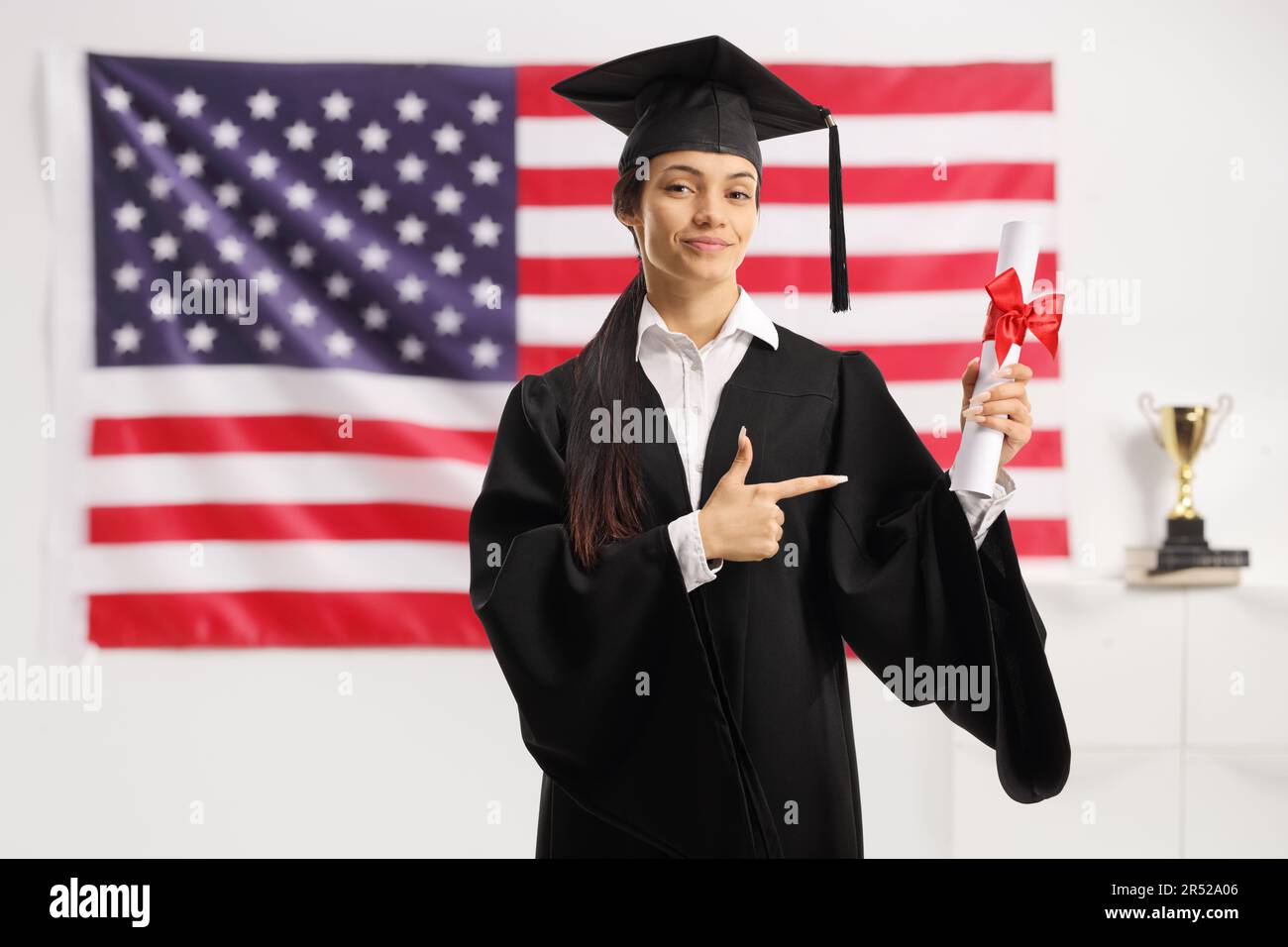 Young female graduate in front of a USA flag holding a degree ...