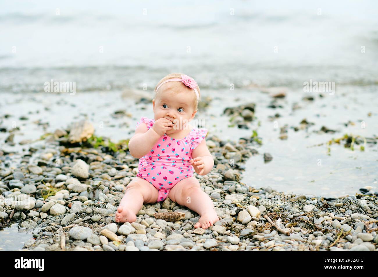 Outdoor portrait of adorable baby girl playing with seaweed by the ...
