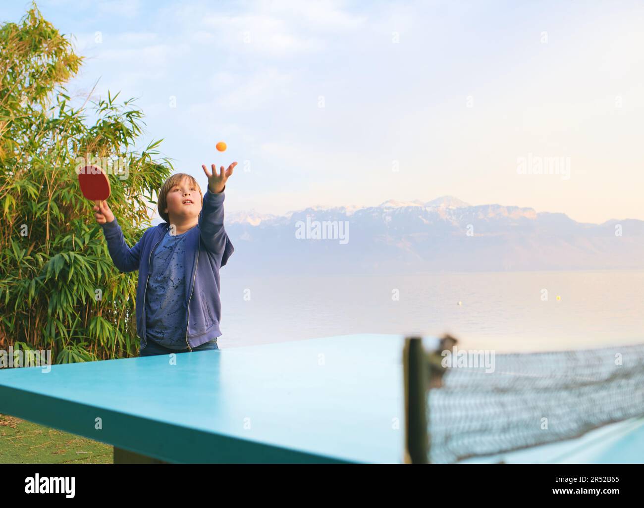 Kid boy playing ping pong by the lake, active lifestyle for children ...