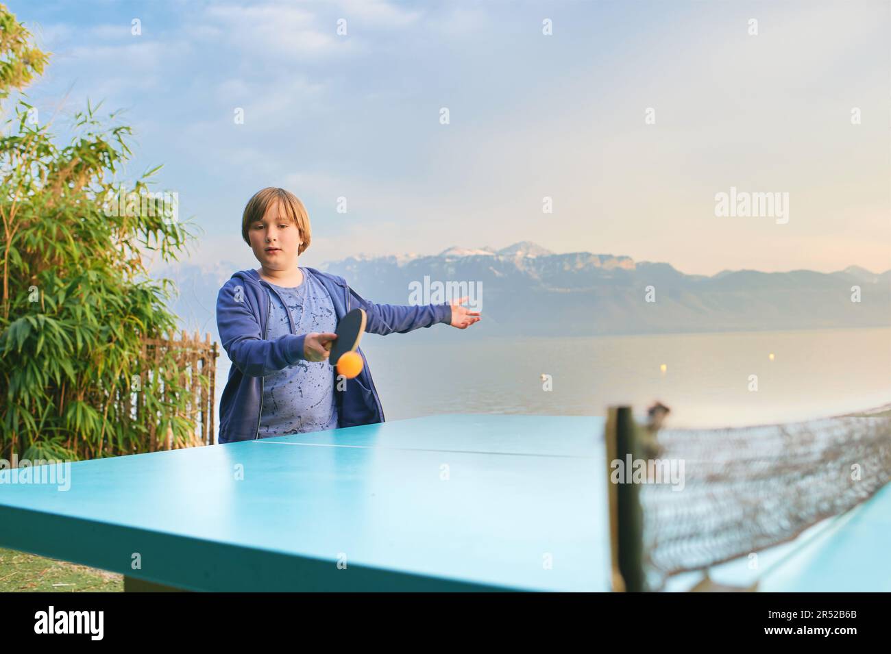 Kid boy playing ping pong by the lake, active lifestyle for children ...