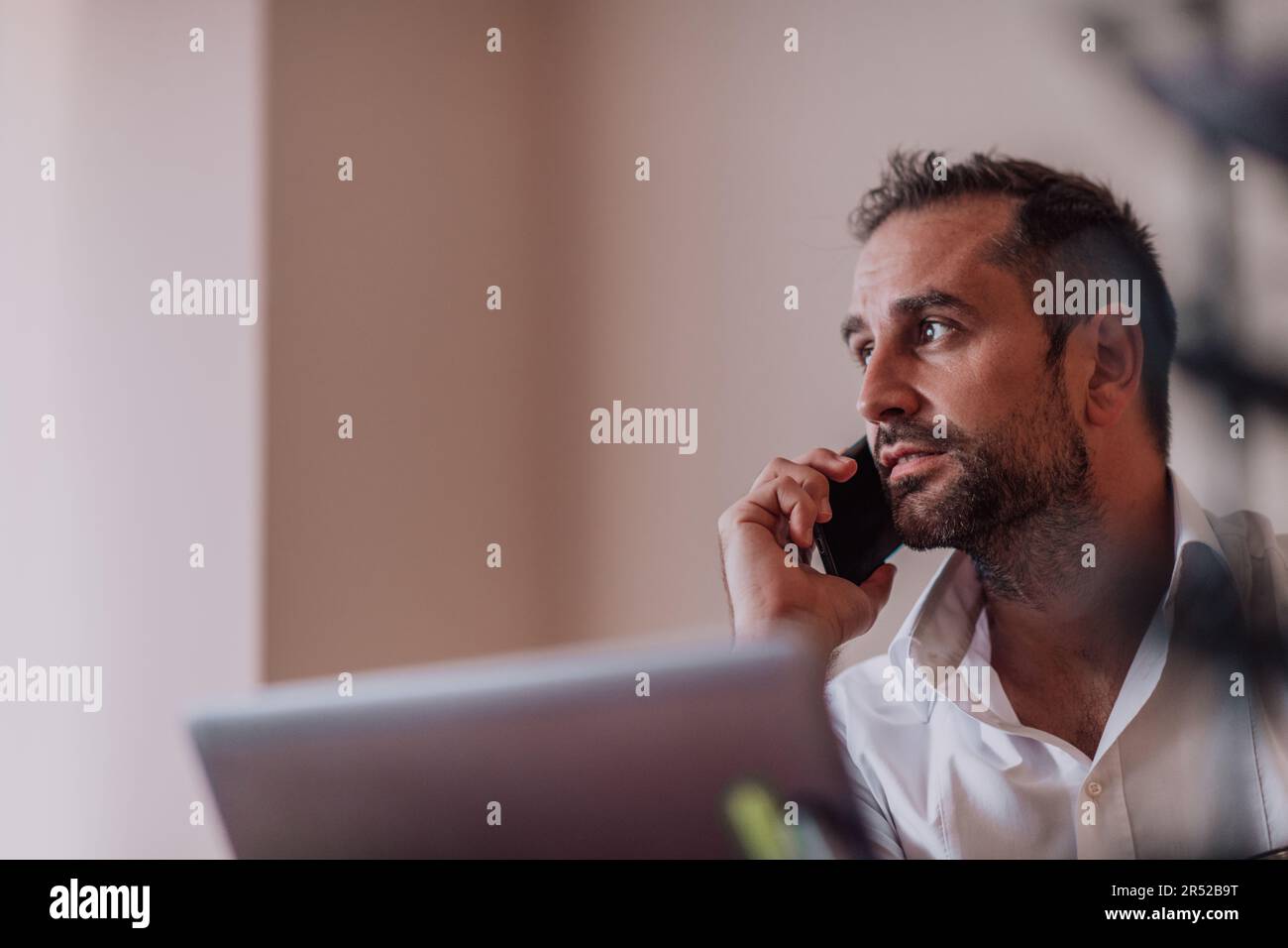 A businessman talking on his smartphone while seated in an office ...