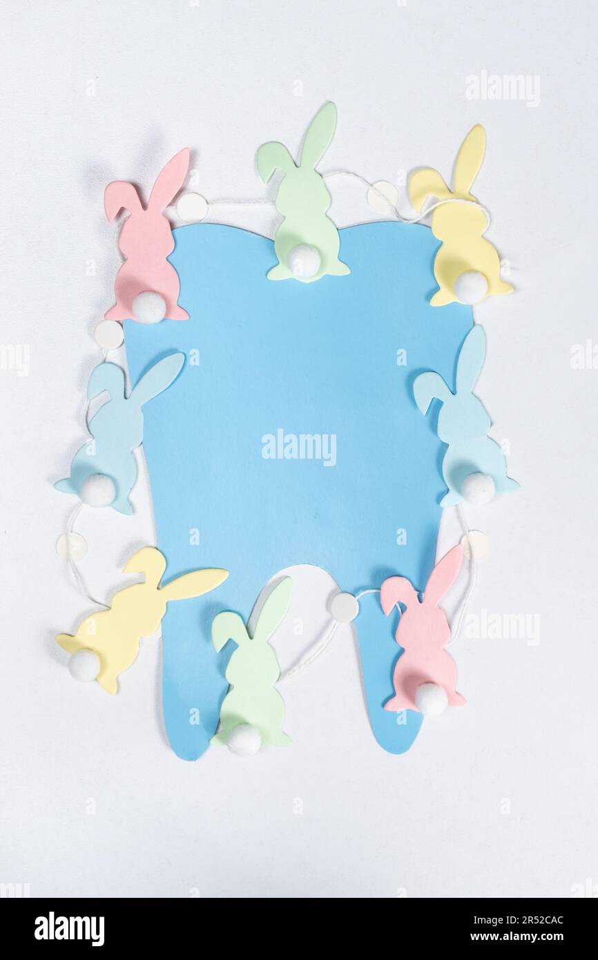 Easter dentistry. Blue tooth and garland of rabbits on a white ...