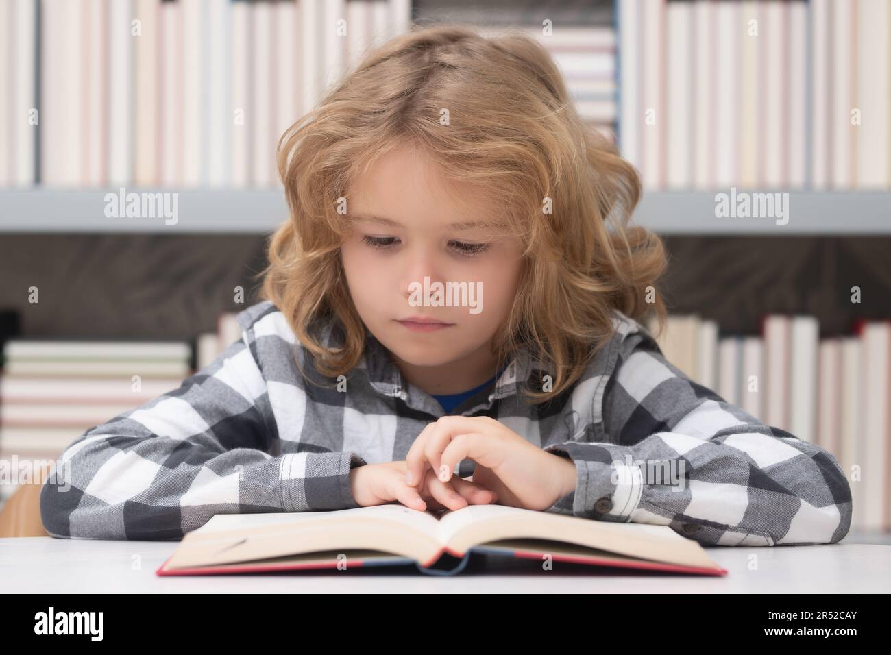 Portrait of school boy reading book in library. Kids development, learn ...