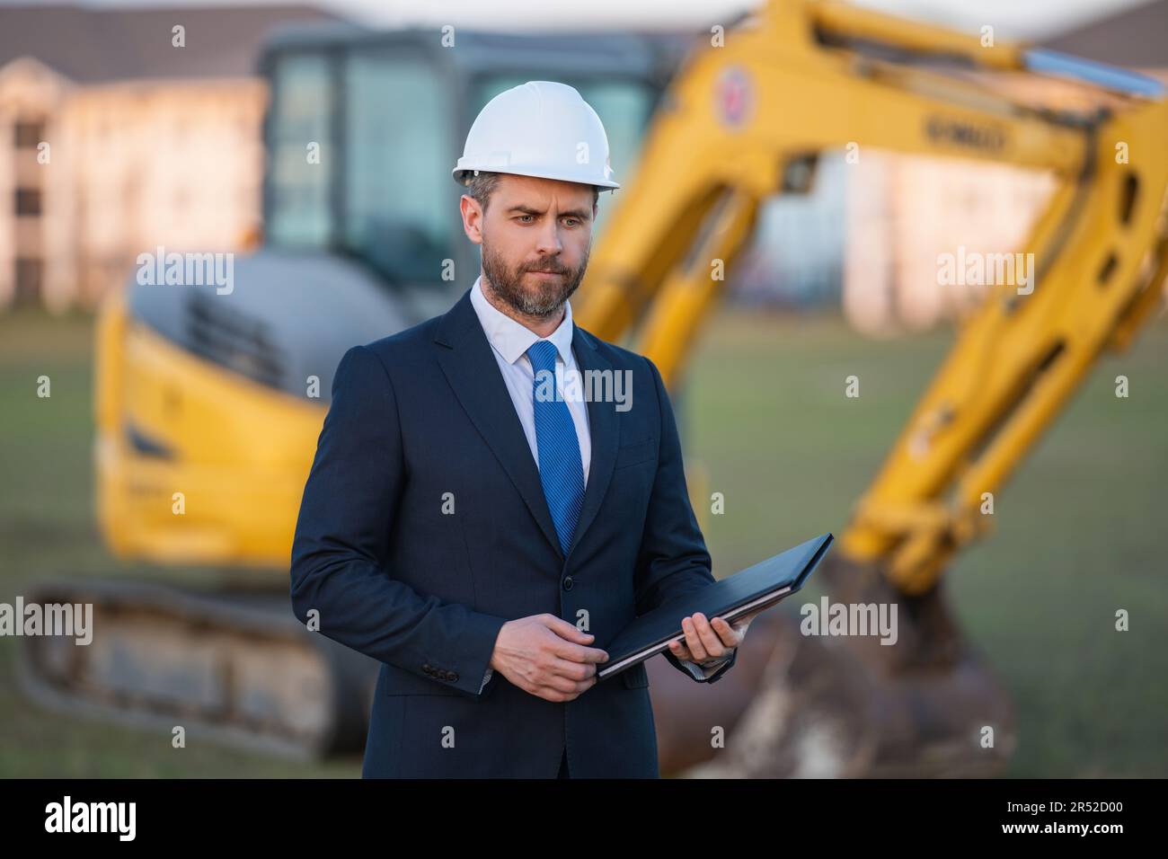 Construction owner near excavator. Confident construction owner in ...