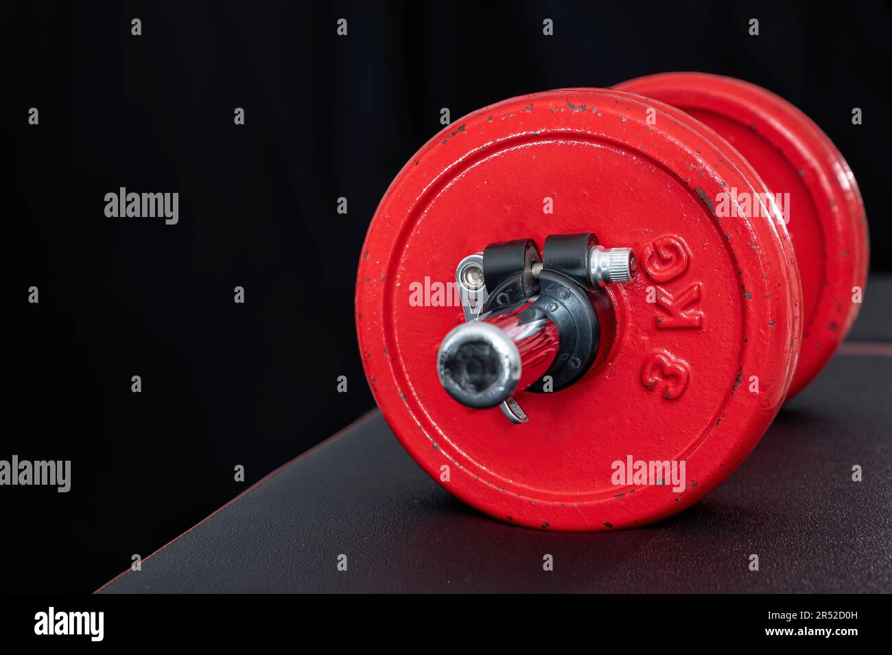 Dumbbell with red weights on a black weight training bench ready to use ...