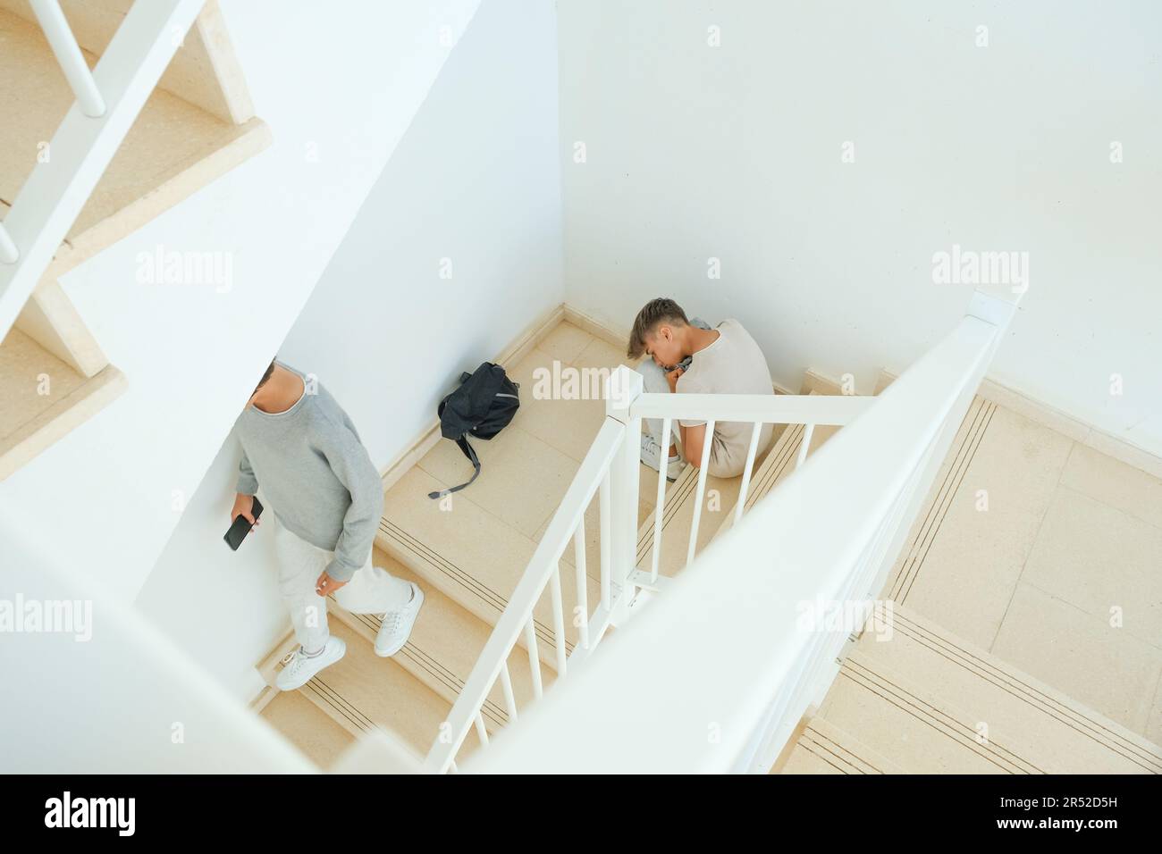 Sad frustrated teenage boy with backpack sitting on staircase while his ...