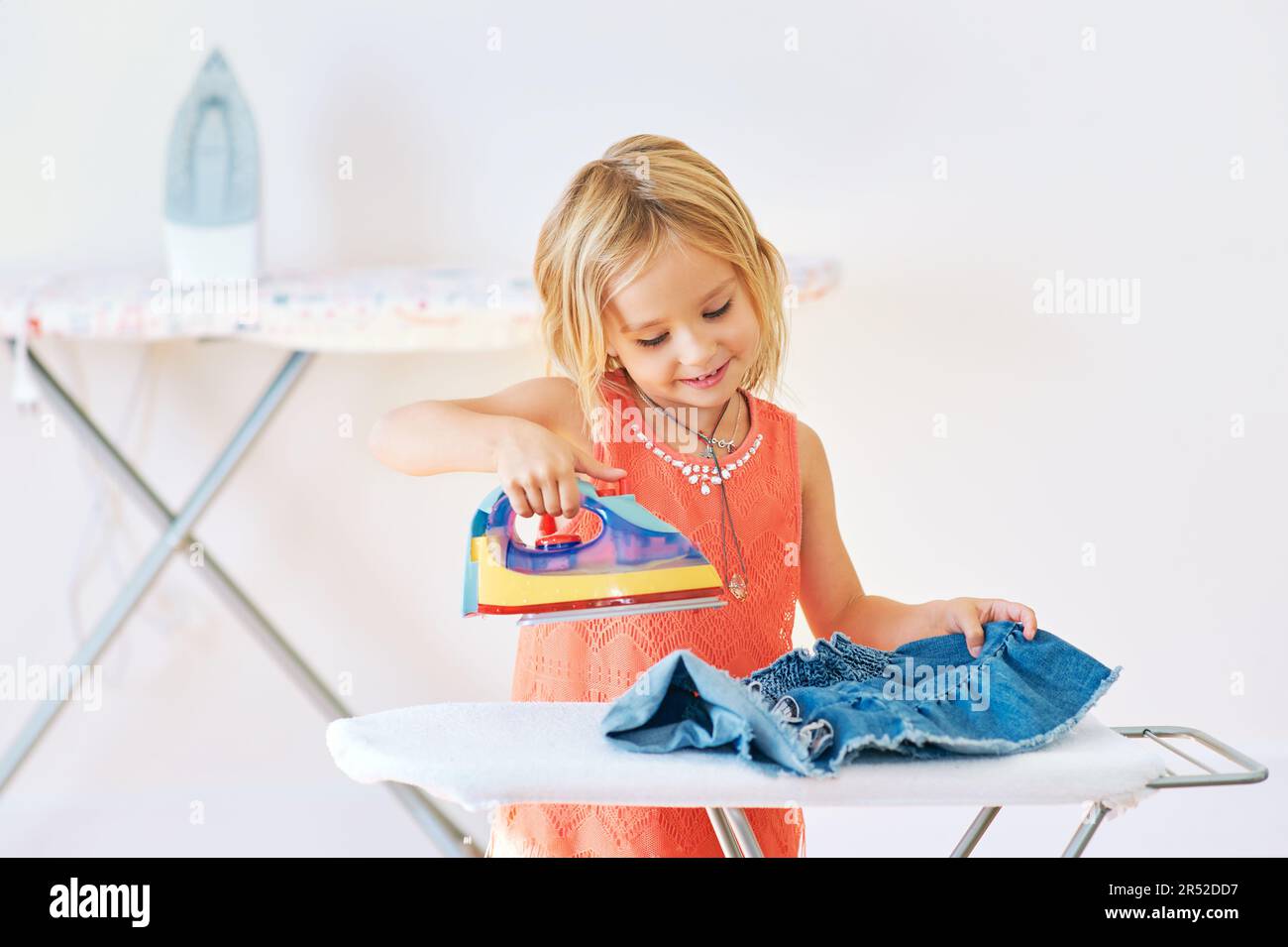 Adorable kid girl playing with toy iron at home Stock Photo - Alamy