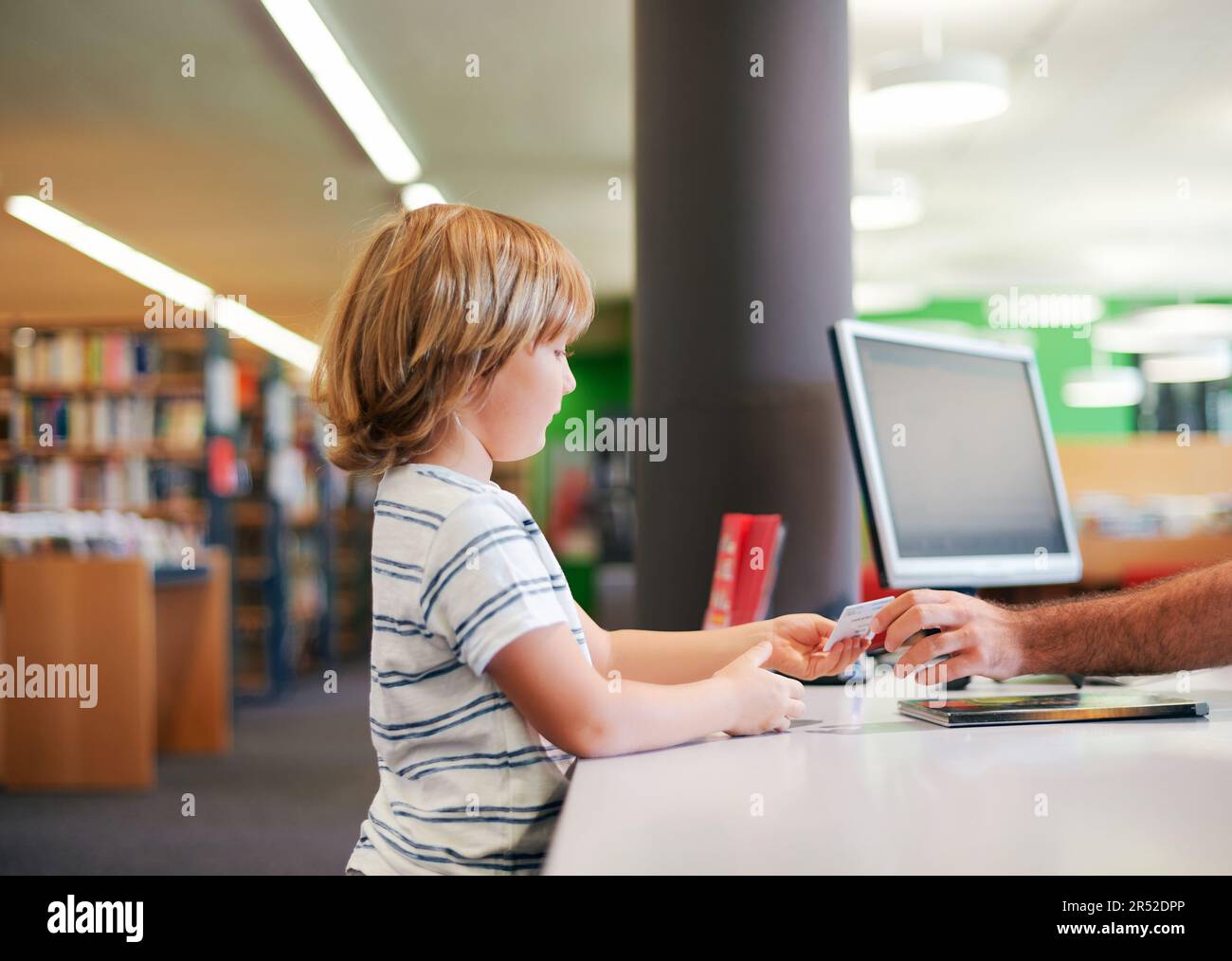 Portrait of cute little boy taking books in library, giving membership ...