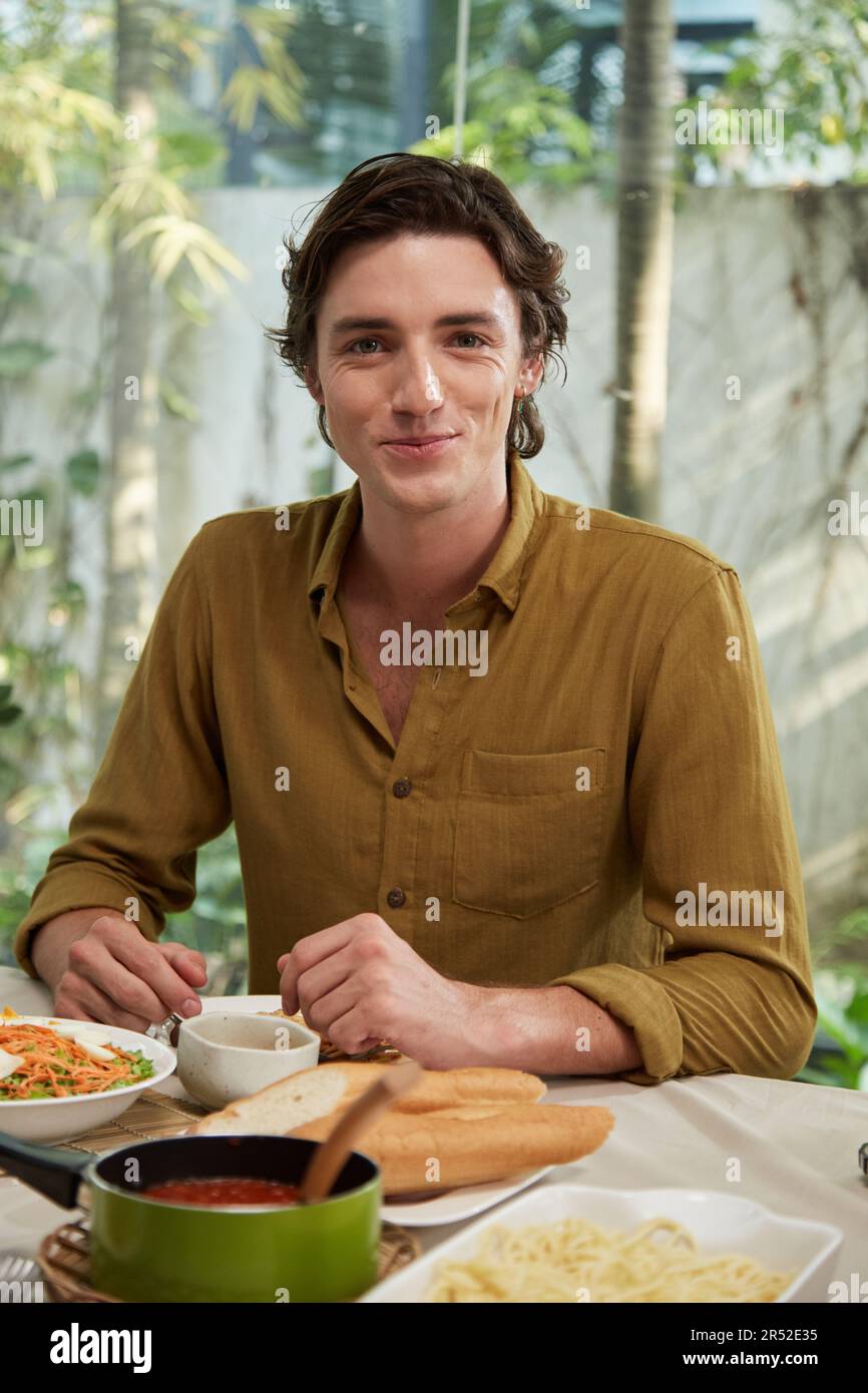 Portrait of happy young man eating tasty homemade dishes Stock Photo ...