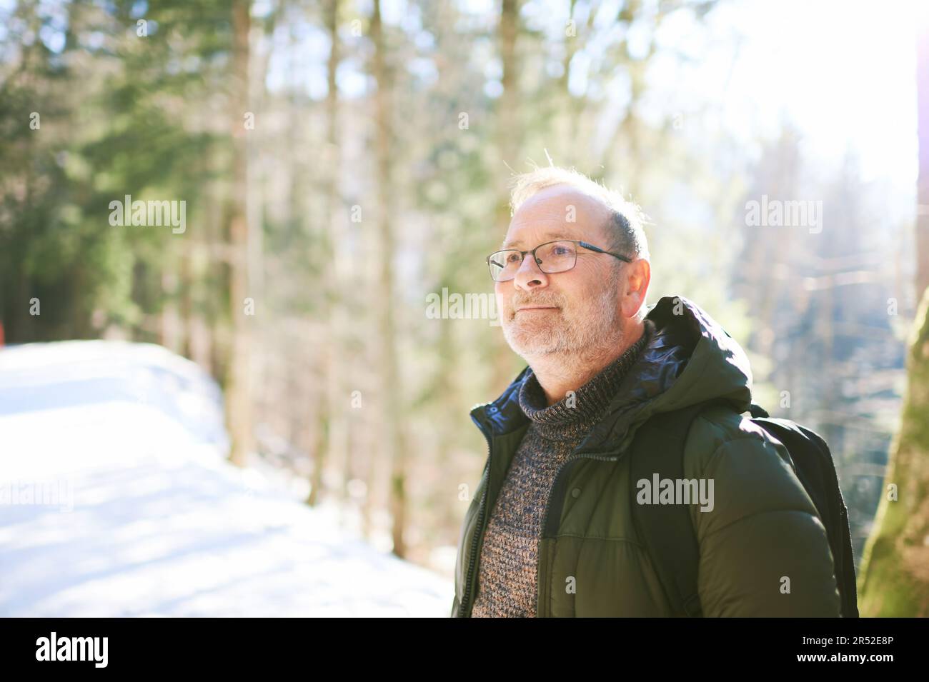 Outdoor portrait of middle age 55 - 60 year old man hiking in winter ...